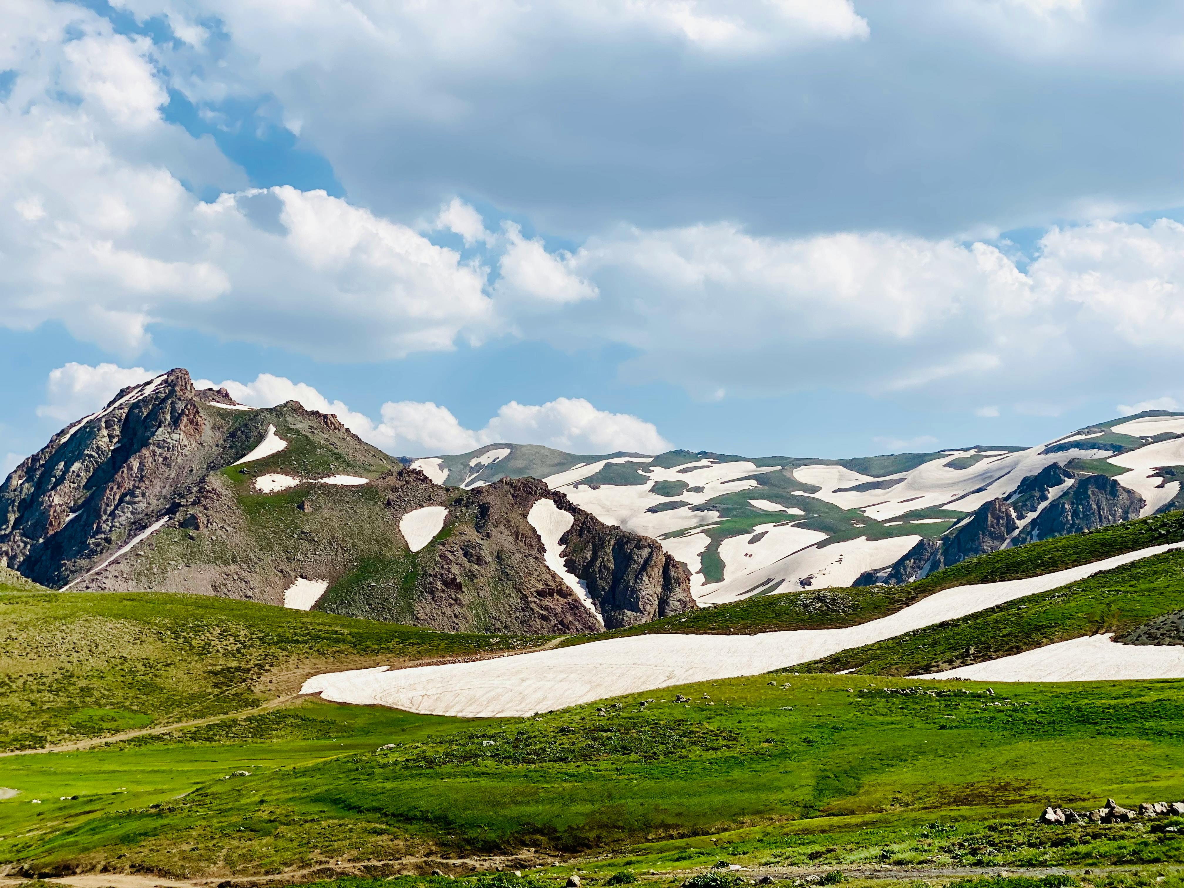 Green Grass Field Near Snow Covered Mountains · Free Stock Photo