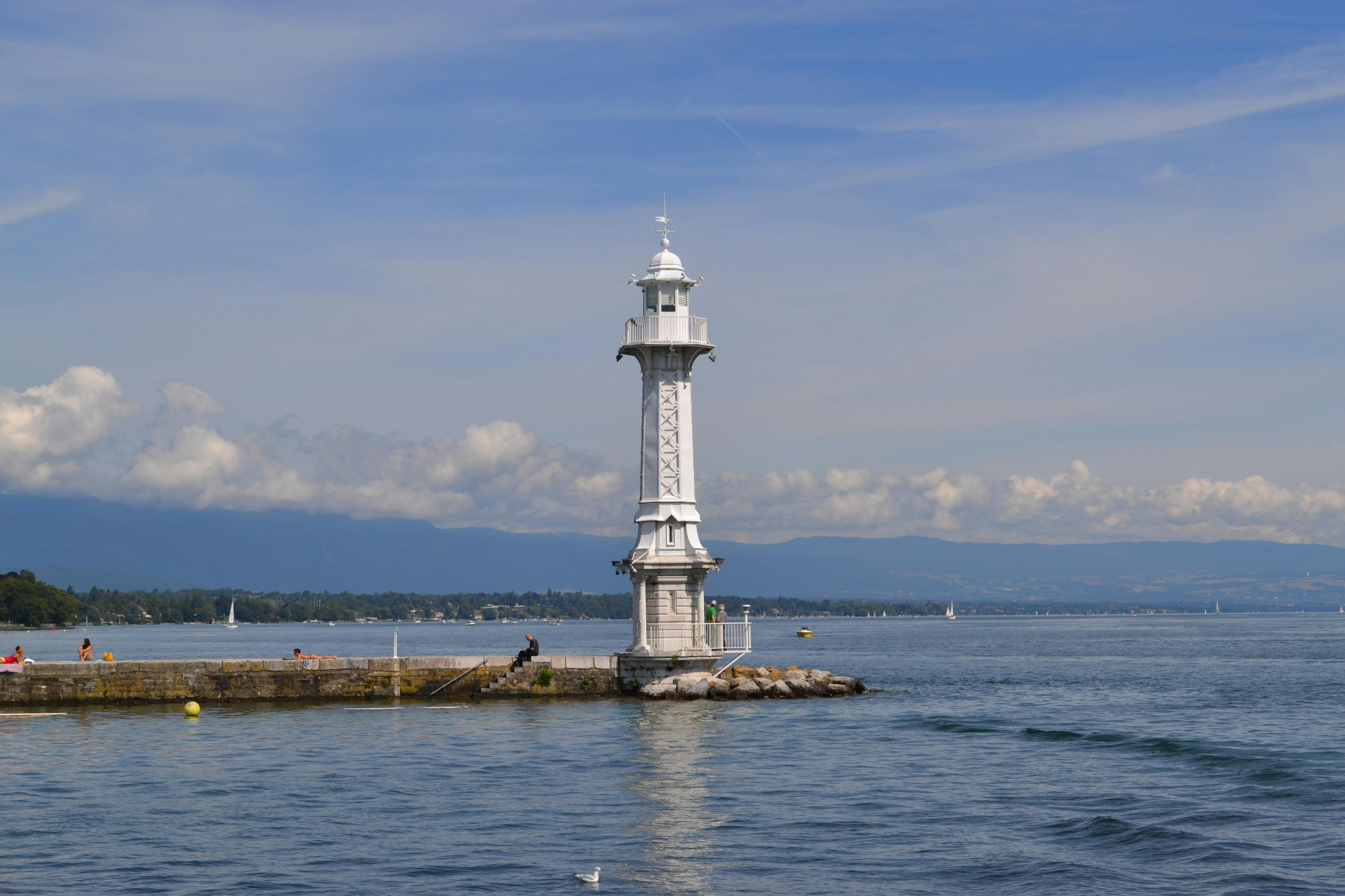 White Lighthouse Near Body of Water Under Blue Sky · Free Stock Photo