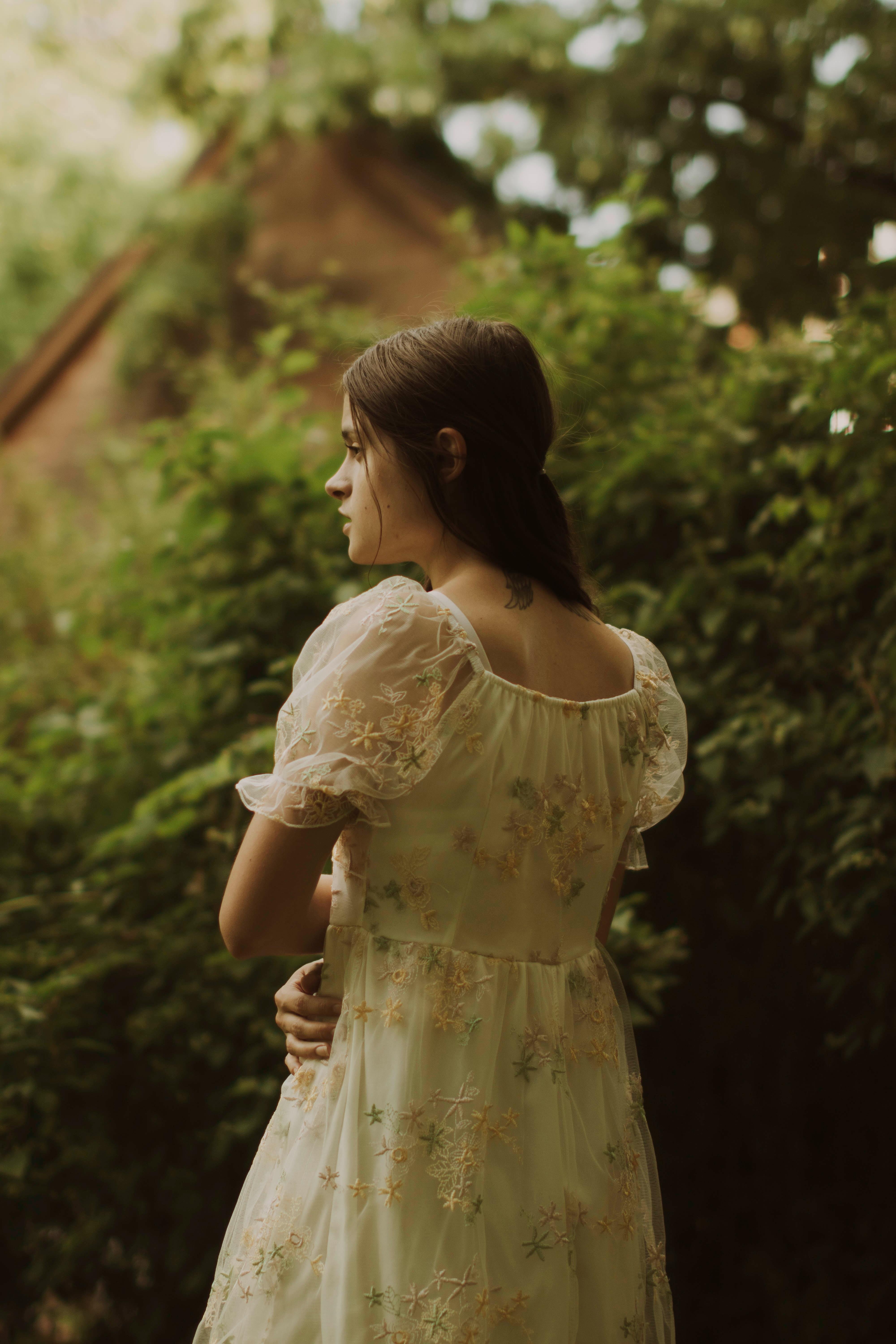 Woman in White Lace Dress Standing Near Green Plants while Looking Afar · Free Stock Photo