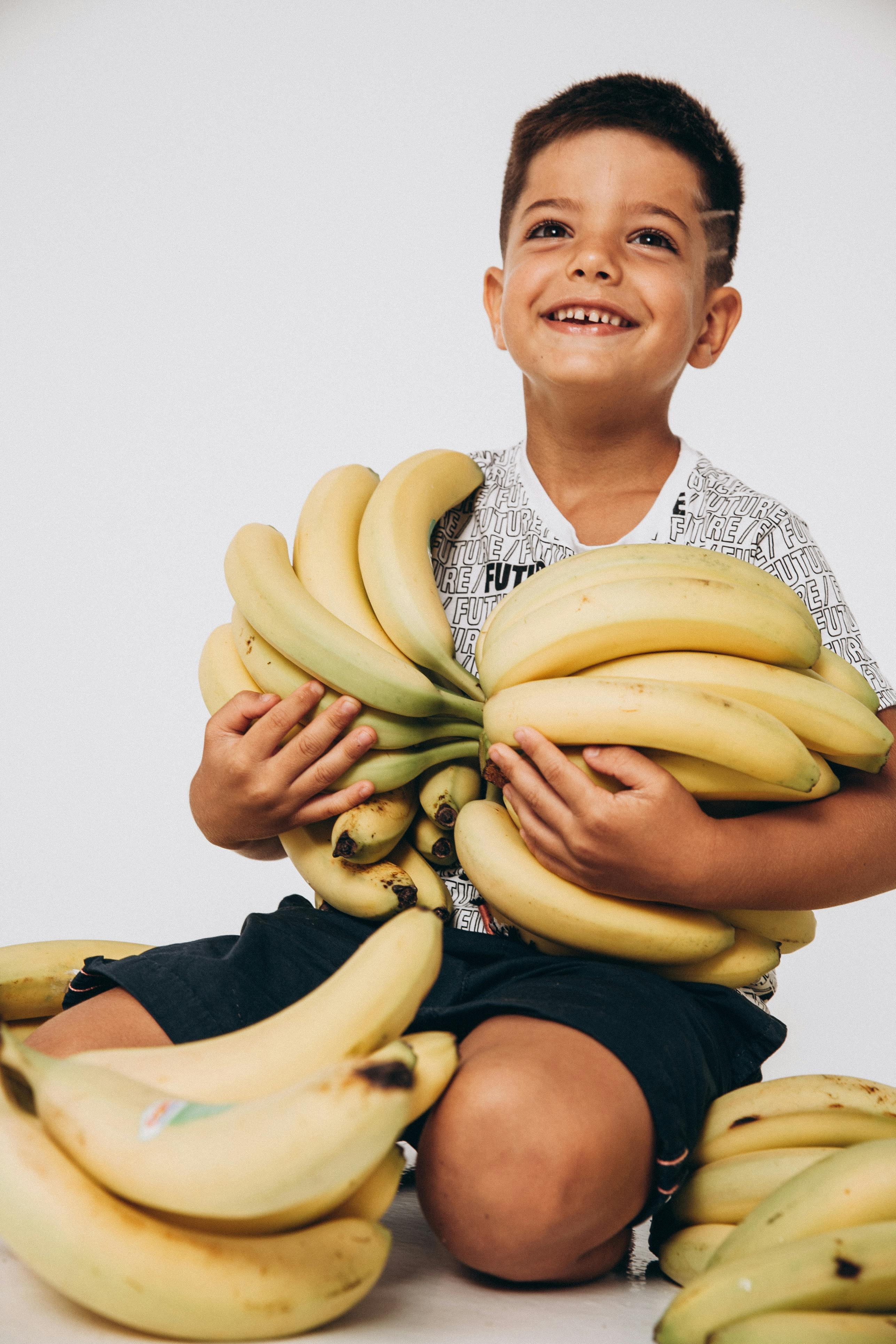 A Young Boy Holding Bananas · Free Stock Photo