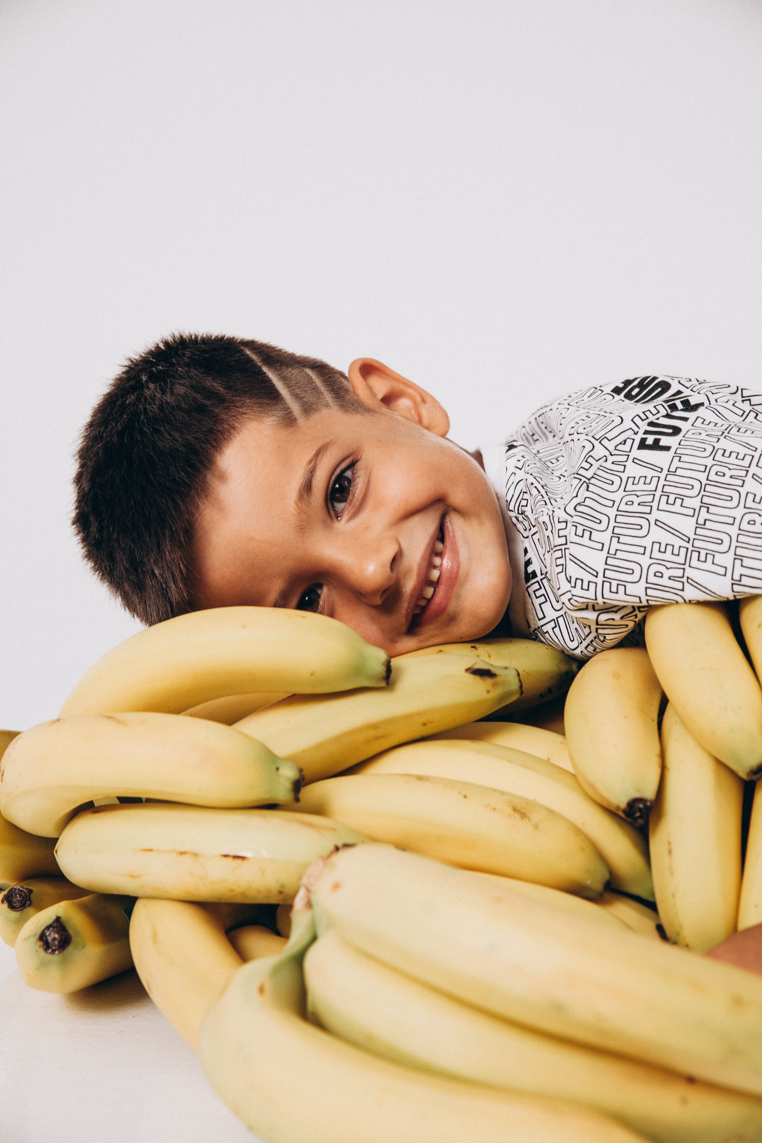 Young Boy in Sunglasses Sticking His Head Through a Pile of Bananas ...