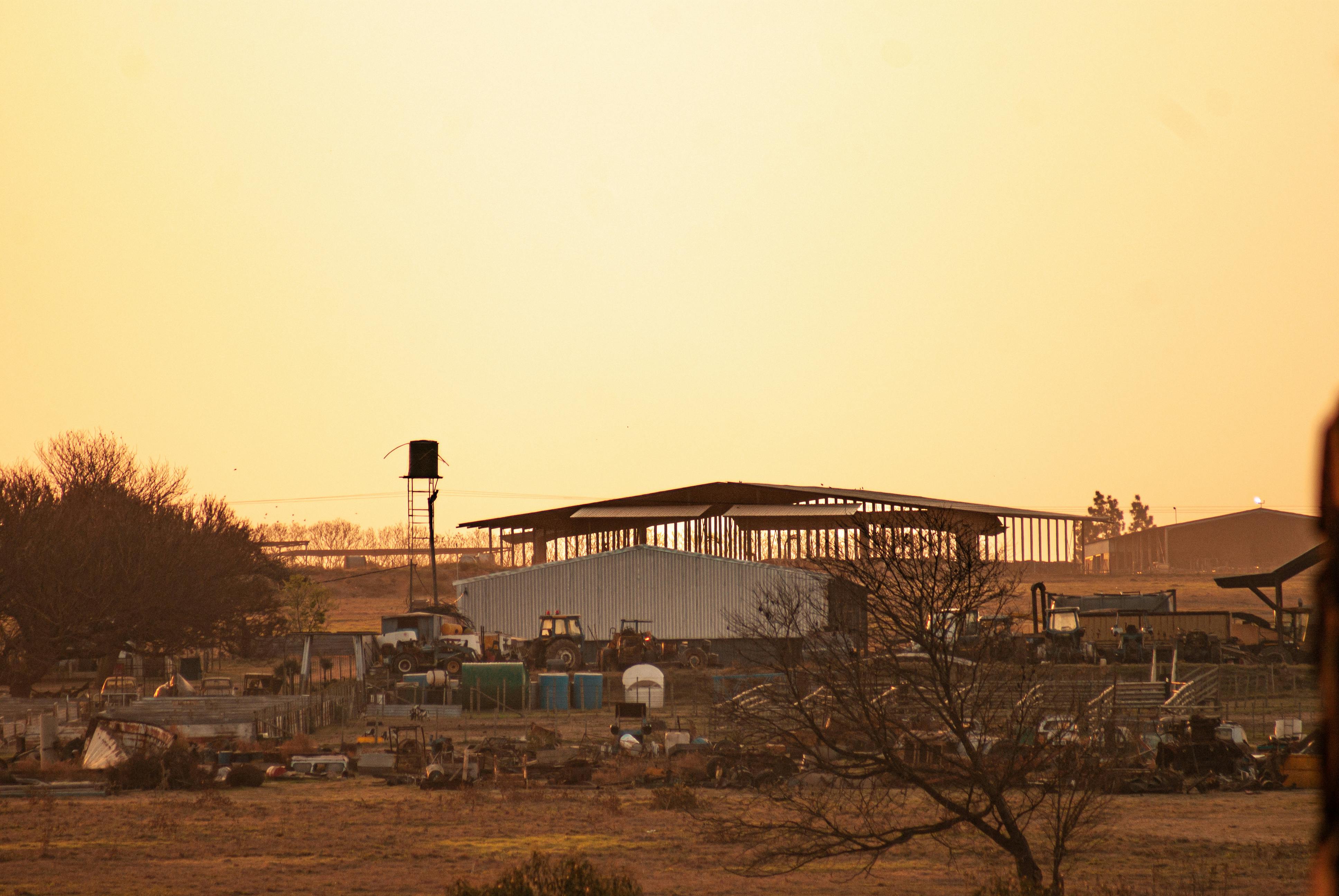 Rusted Farm Equipment in Front of Abandoned Warehouse · Free Stock Photo