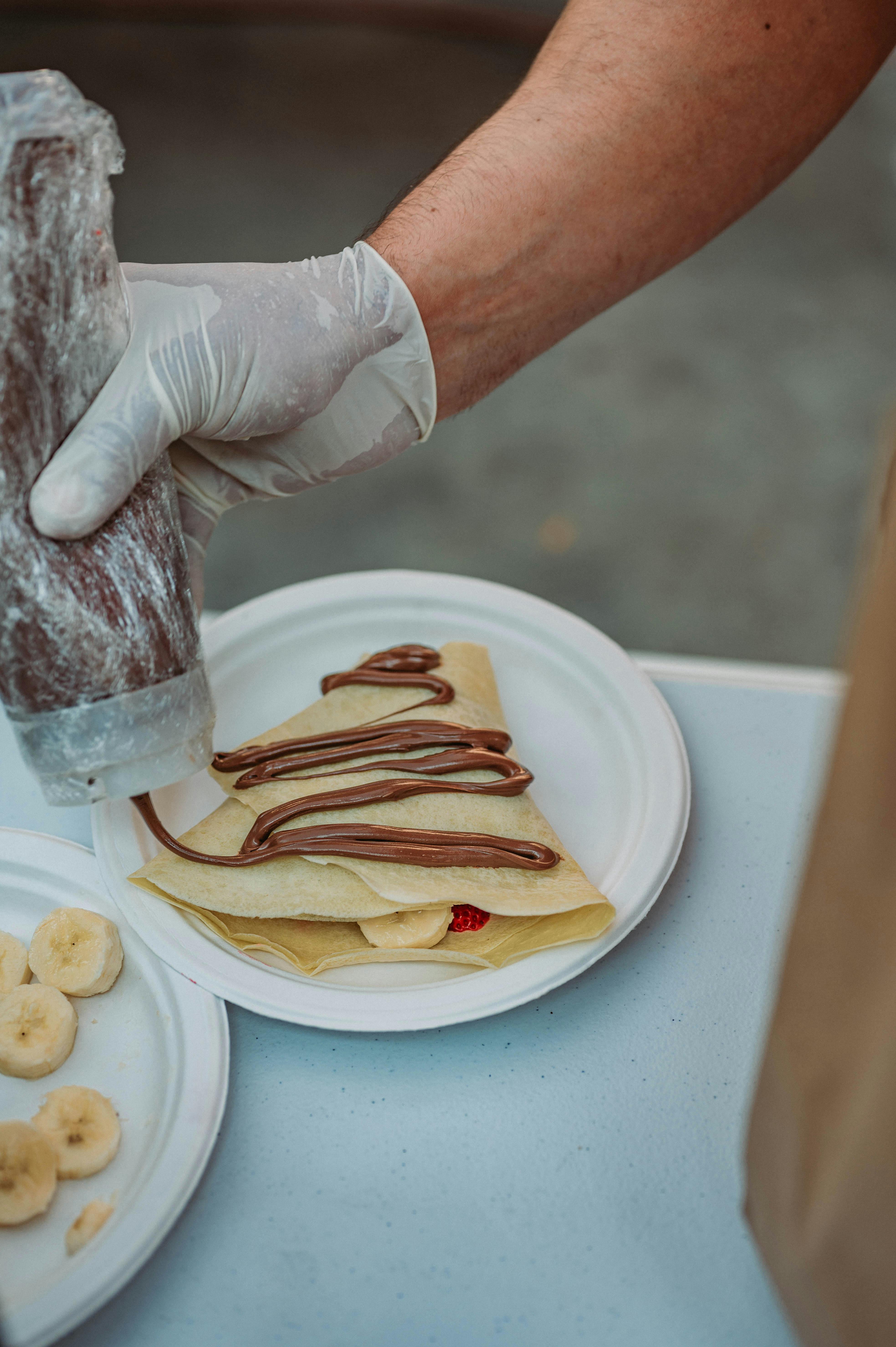 Little cute girl spreading jam and cream on crepe · Free Stock Photo
