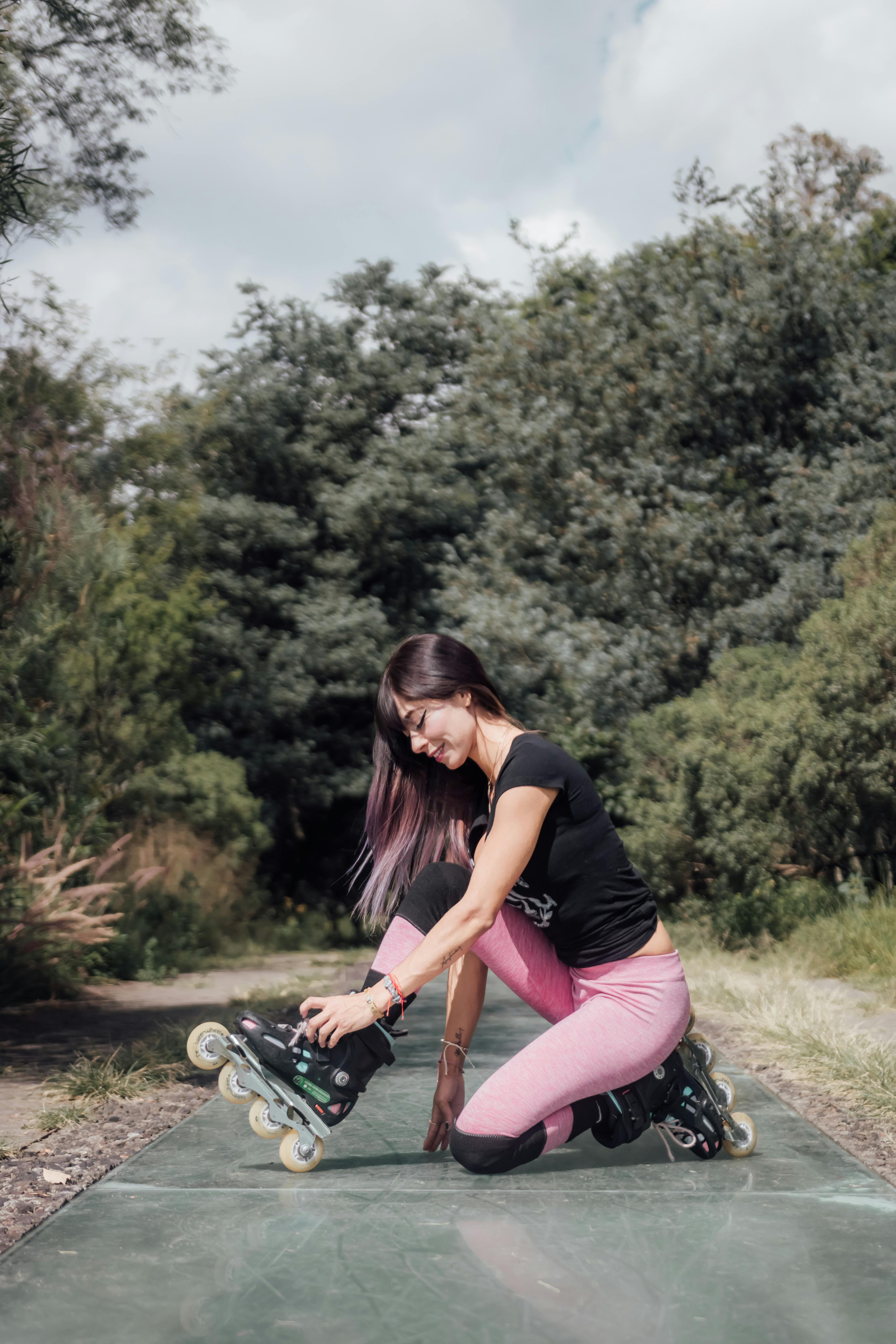 Young Woman Kneeling to Adjust Her Rollers · Free Stock Photo