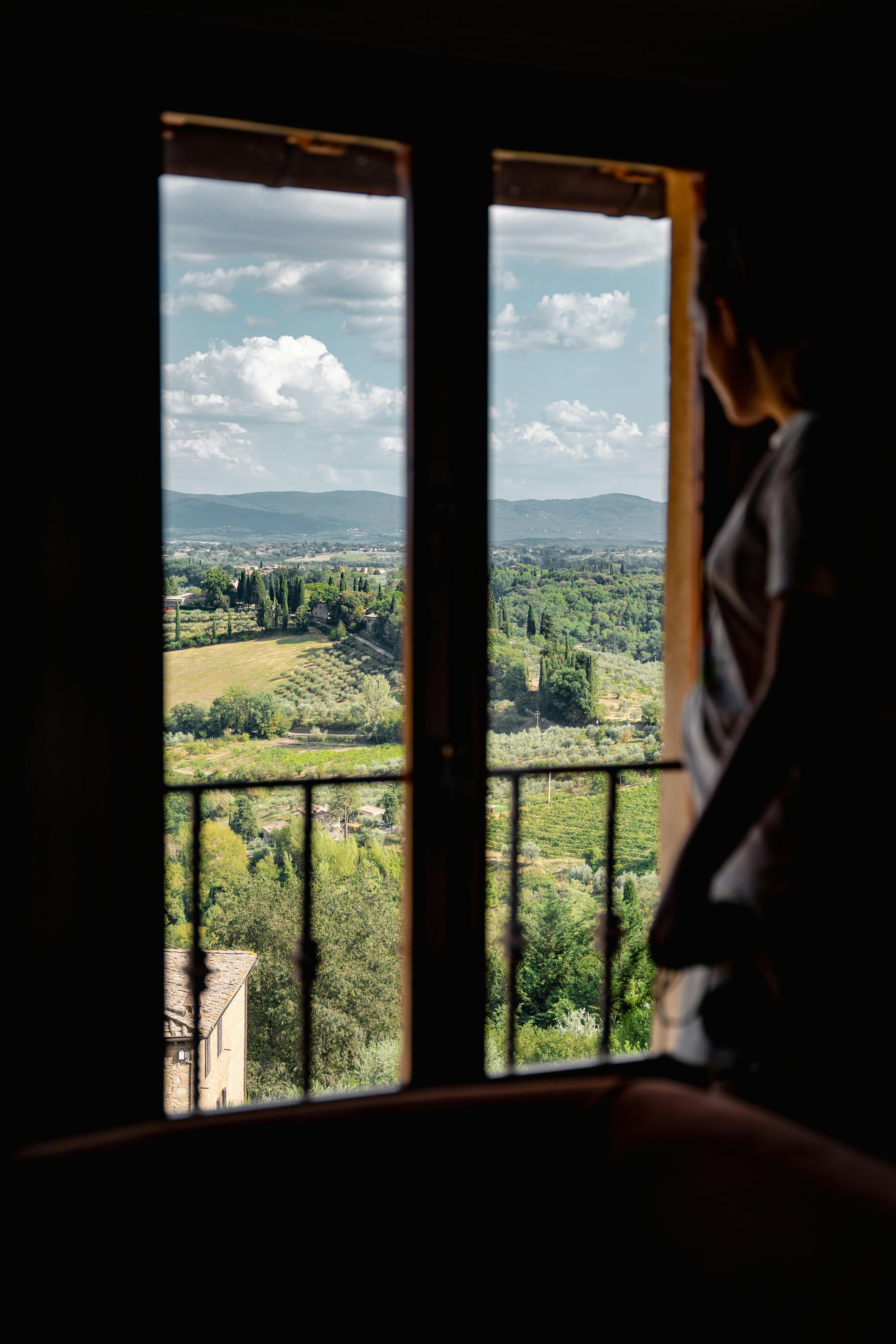 Woman Standing in Room Darkness with Countryside behind Windows · Free ...