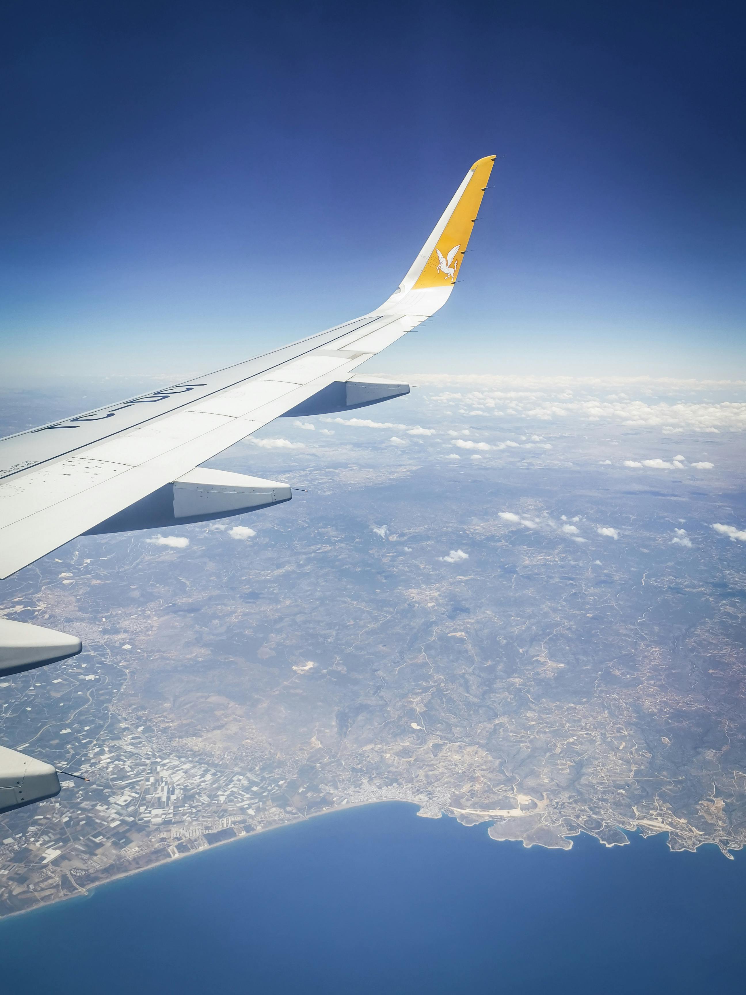 White and Yellow Airplane Flying Over an Ocean · Free Stock Photo