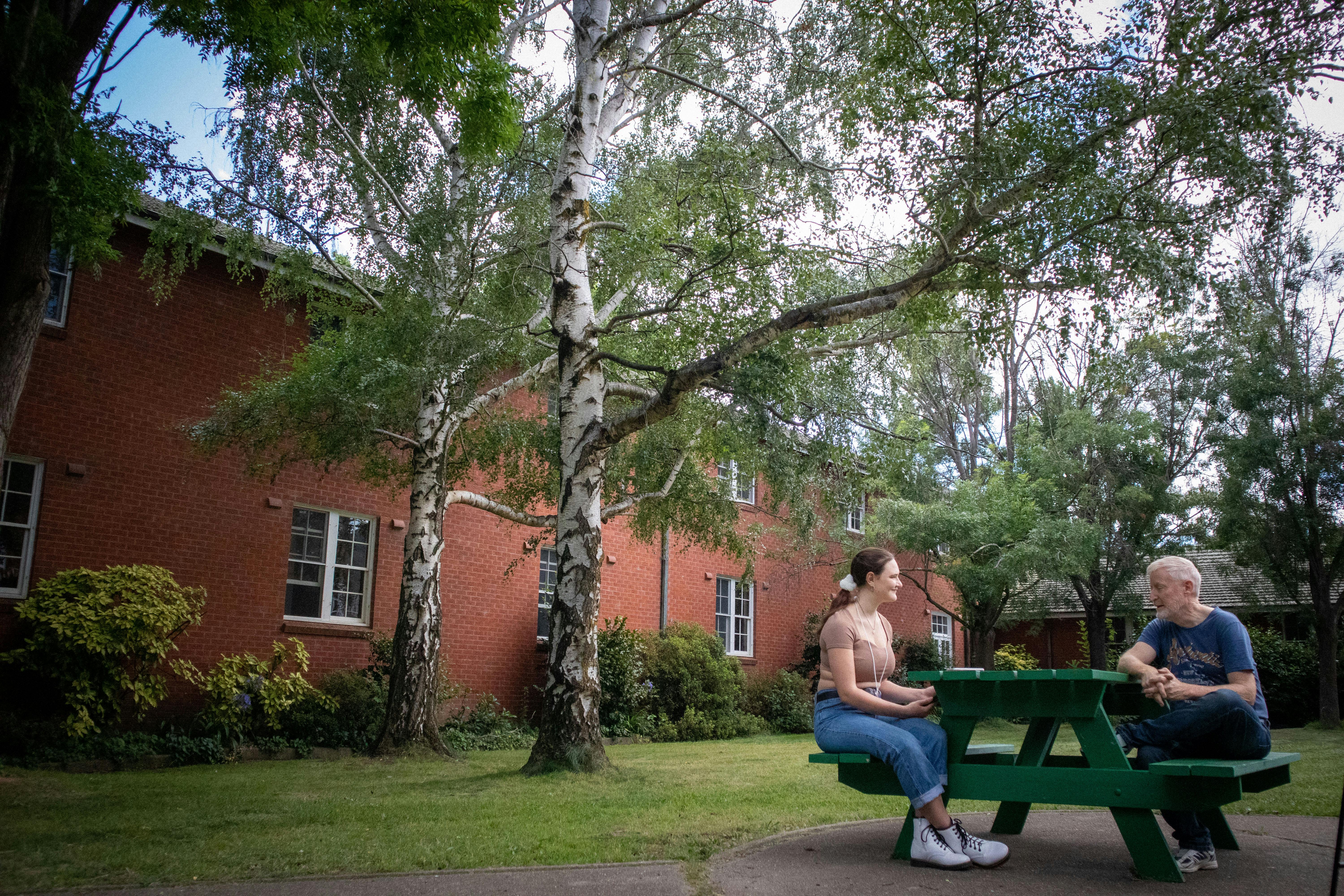 Man and Woman Talking on a Picnic Bench · Free Stock Photo
