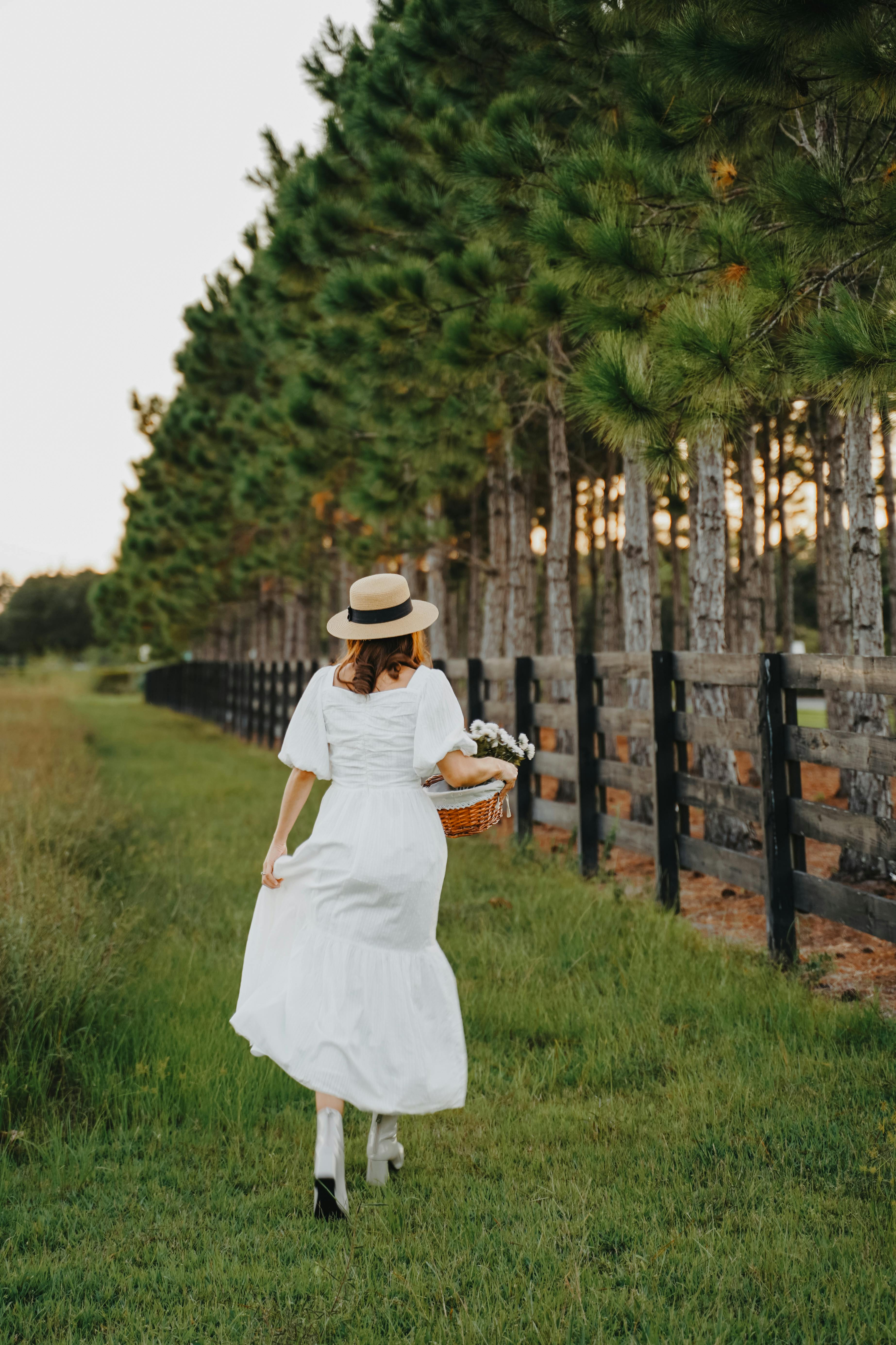 Woman in White Dress Walking Along Trees · Free Stock Photo