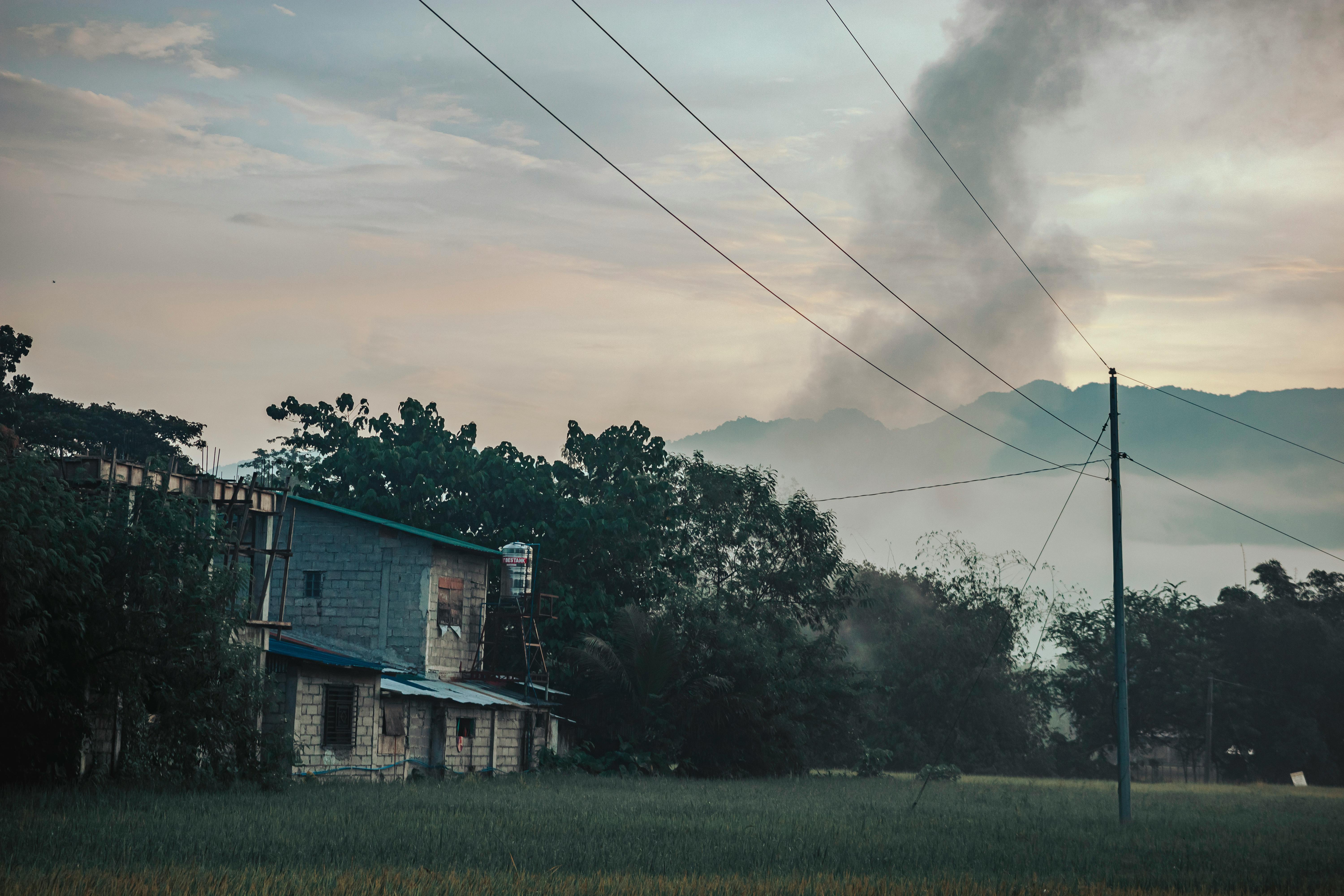 A Gray Unpainted House Near Gray Smoke · Free Stock Photo