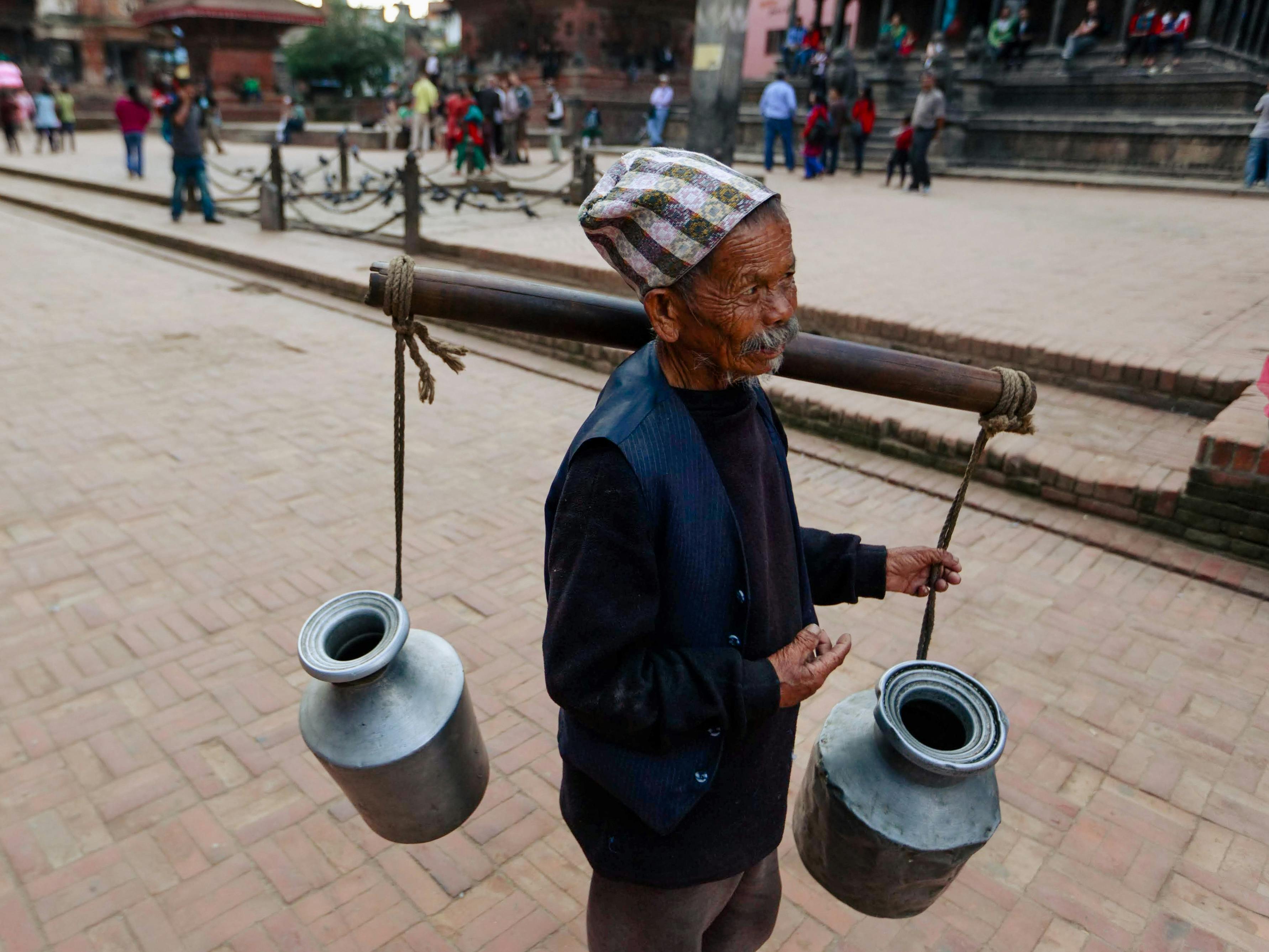 A Man Carrying Milk Jars · Free Stock Photo