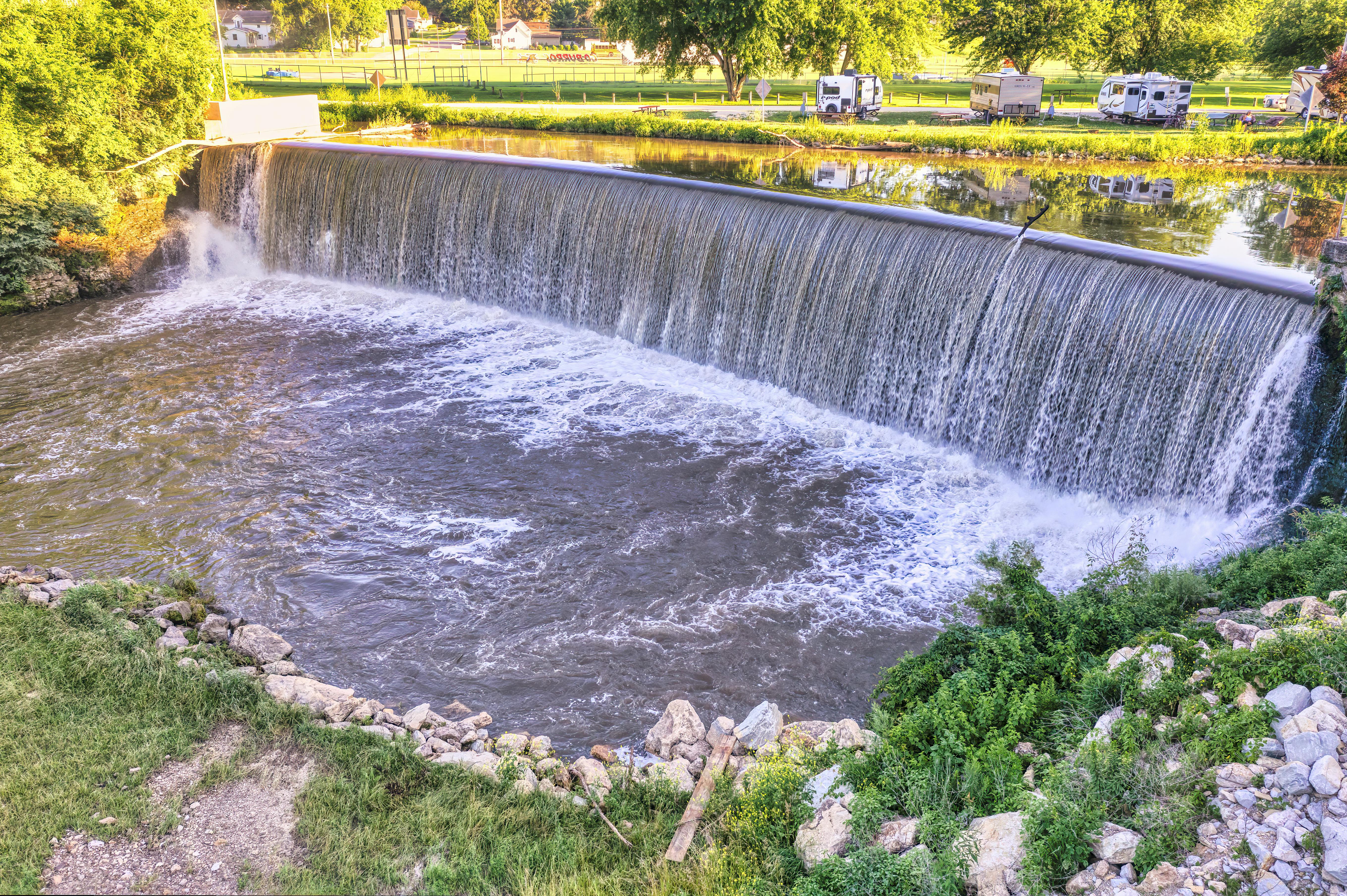 Photo of a Dam on a River and Campers in Background · Free Stock Photo