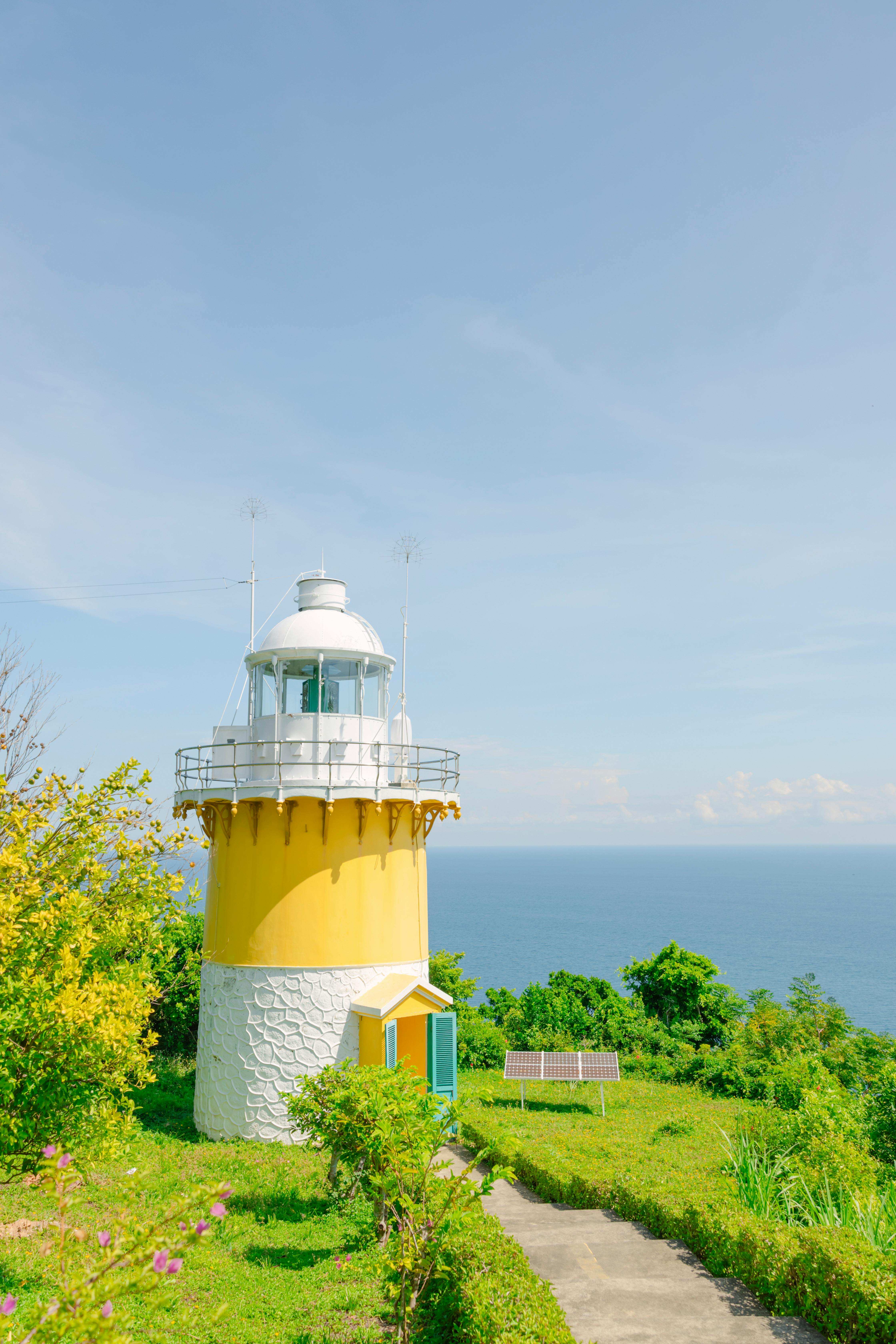 White and Yellow Lighthouse Near Green Trees · Free Stock Photo