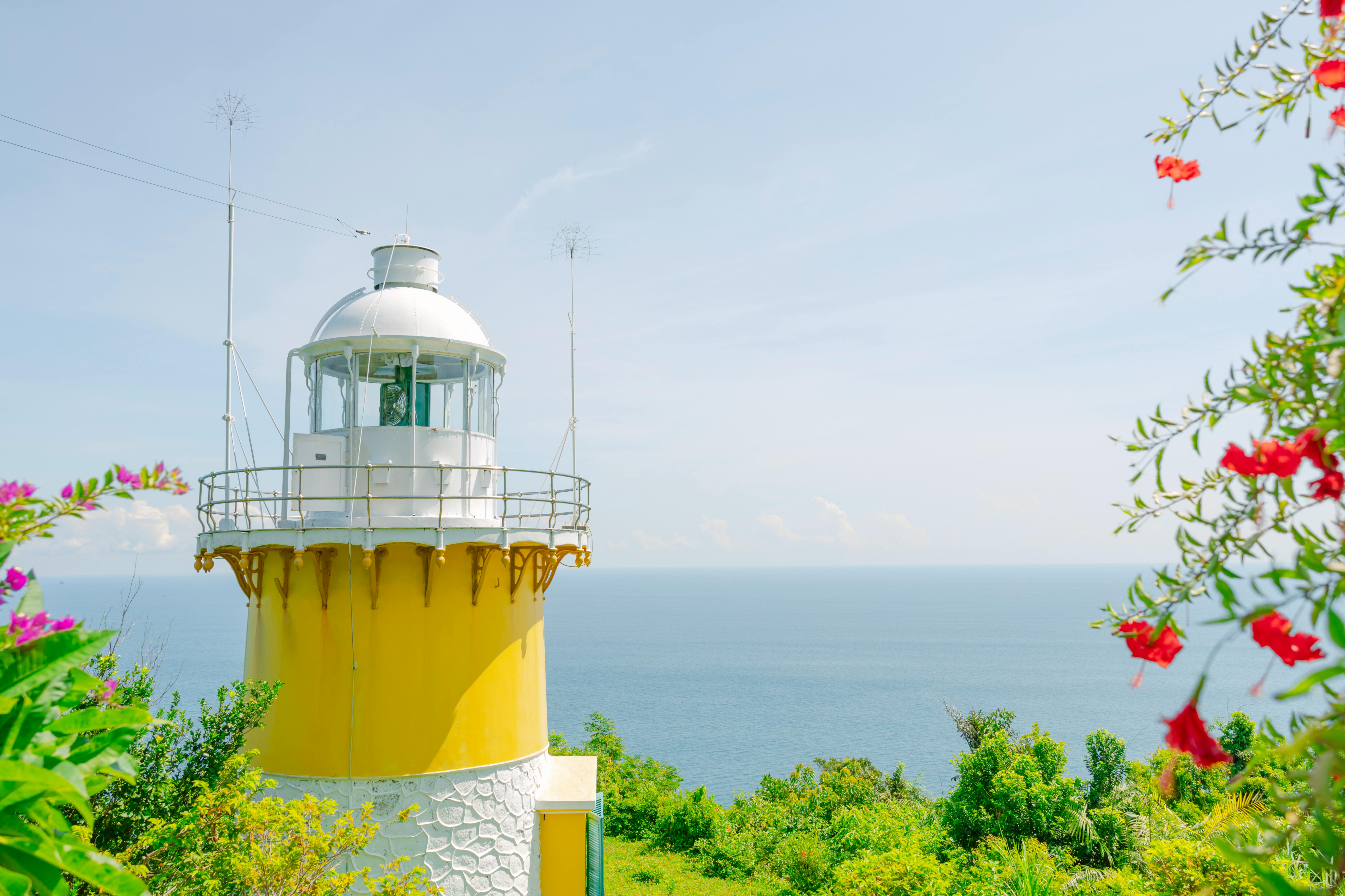 A White and Yellow Lighthouse by the Sea · Free Stock Photo
