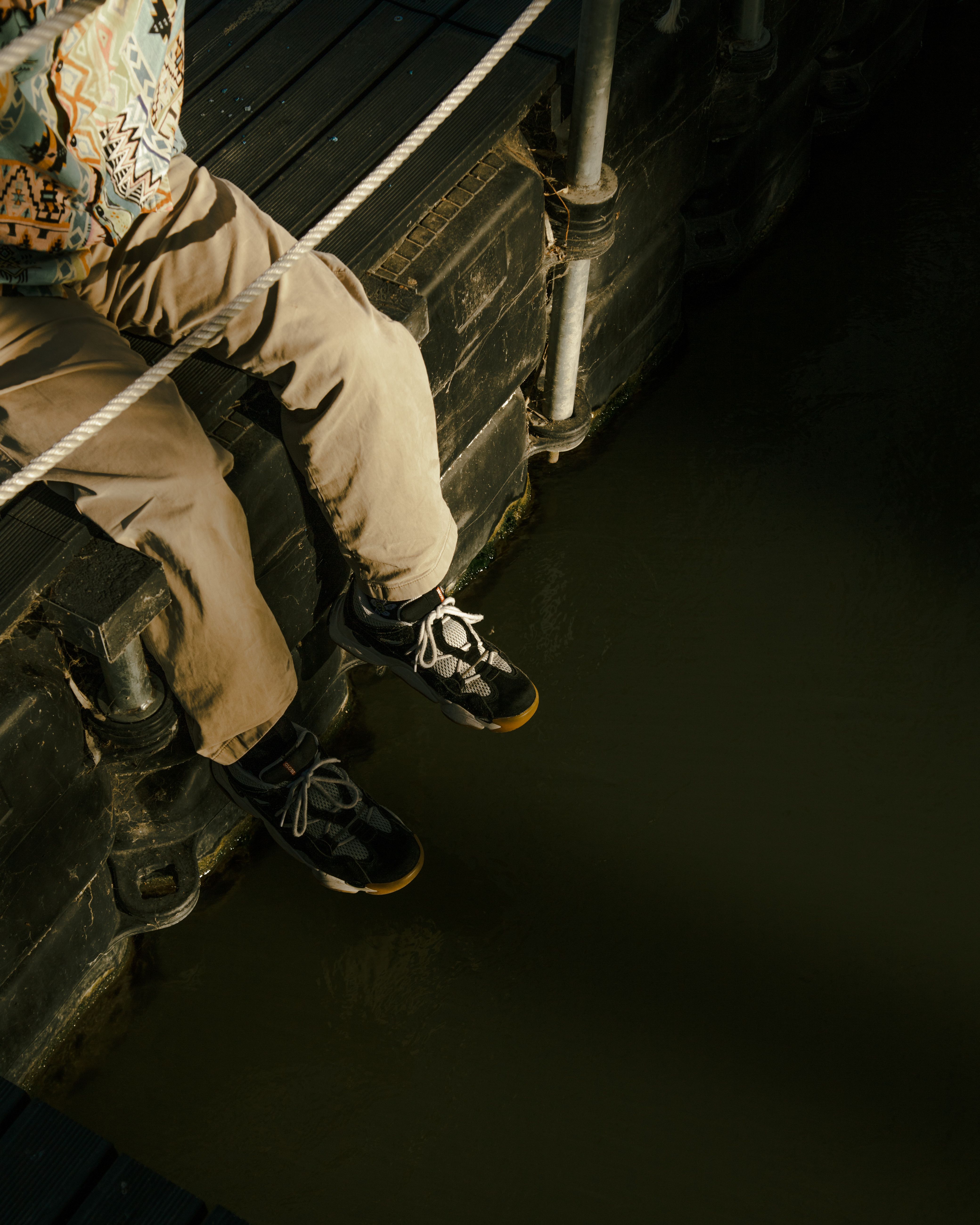 Legs of a Person Sitting on a Ledge over Water · Free Stock Photo