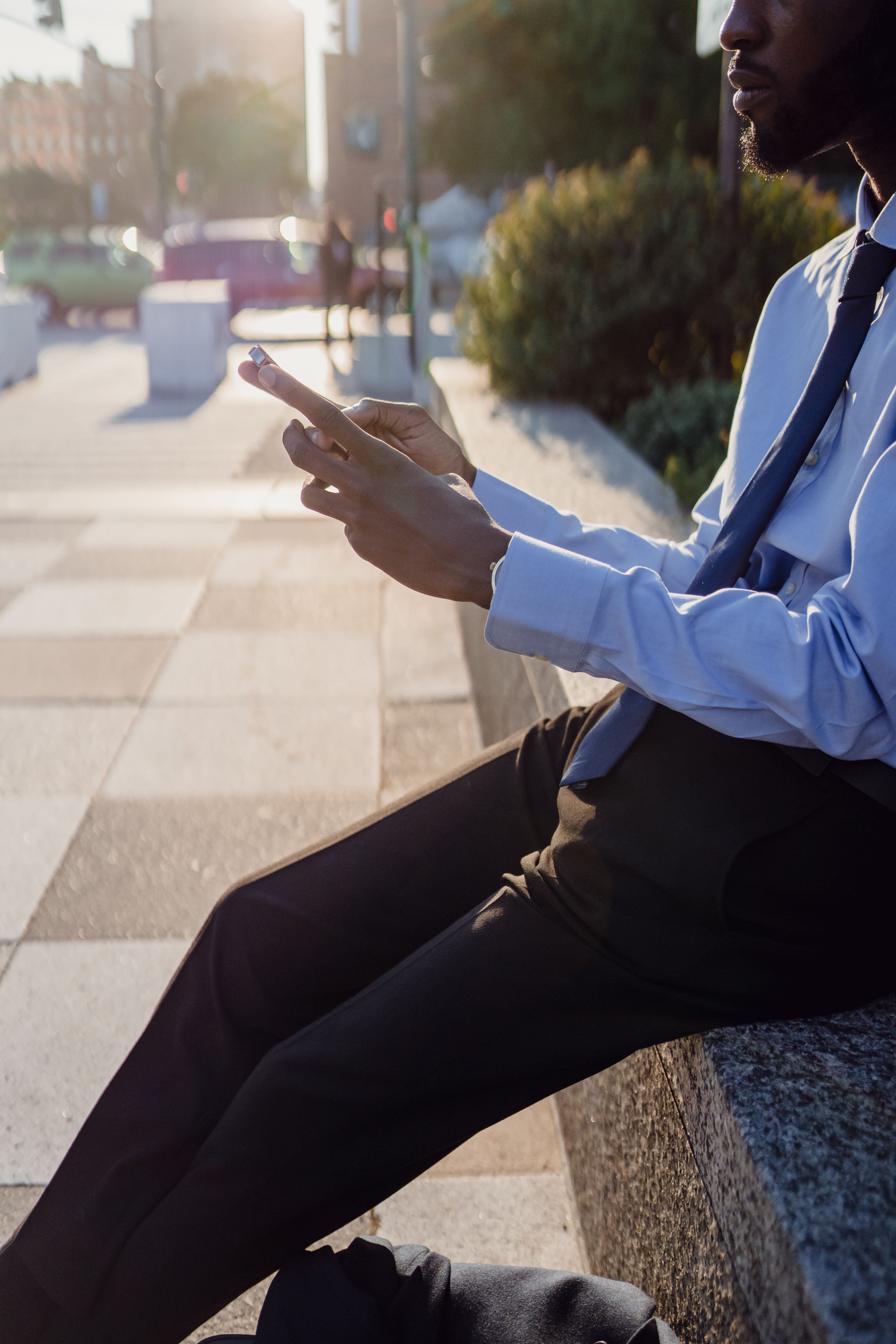 Man Sitting on Gray Bench While Using Mobile Phone · Free Stock Photo