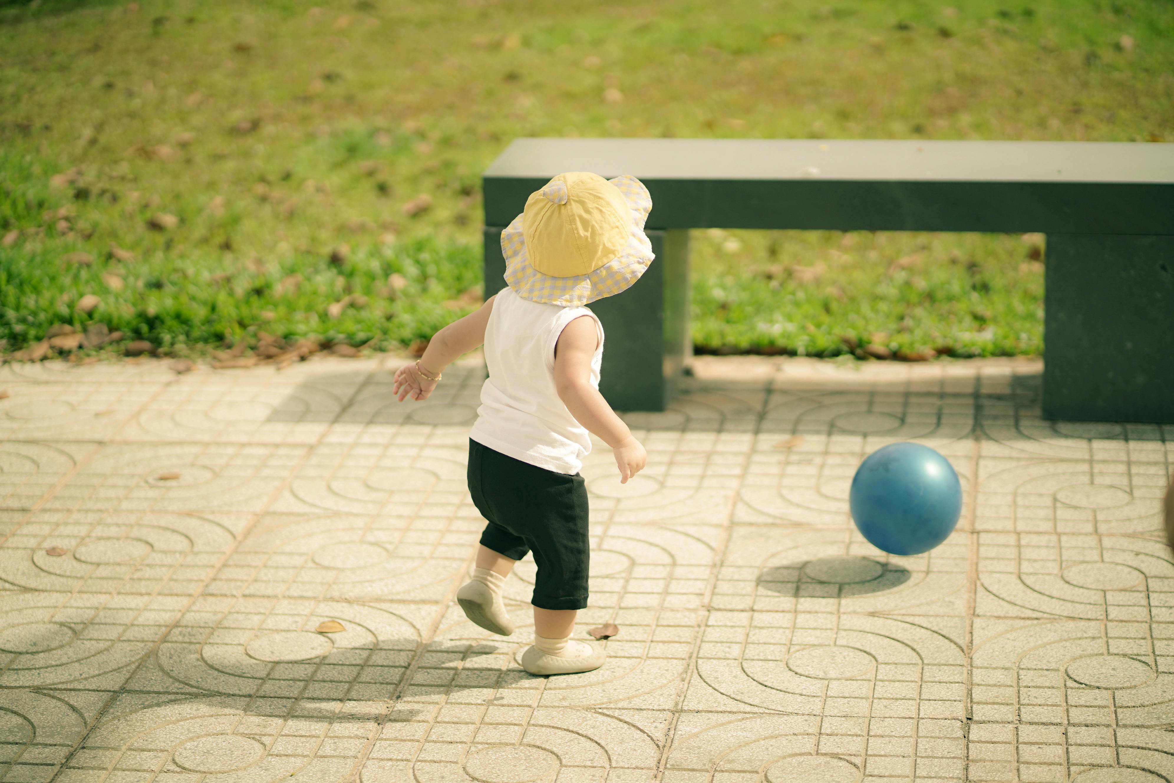 Backview of a Cute Child running after a Blue Ball · Free Stock Photo