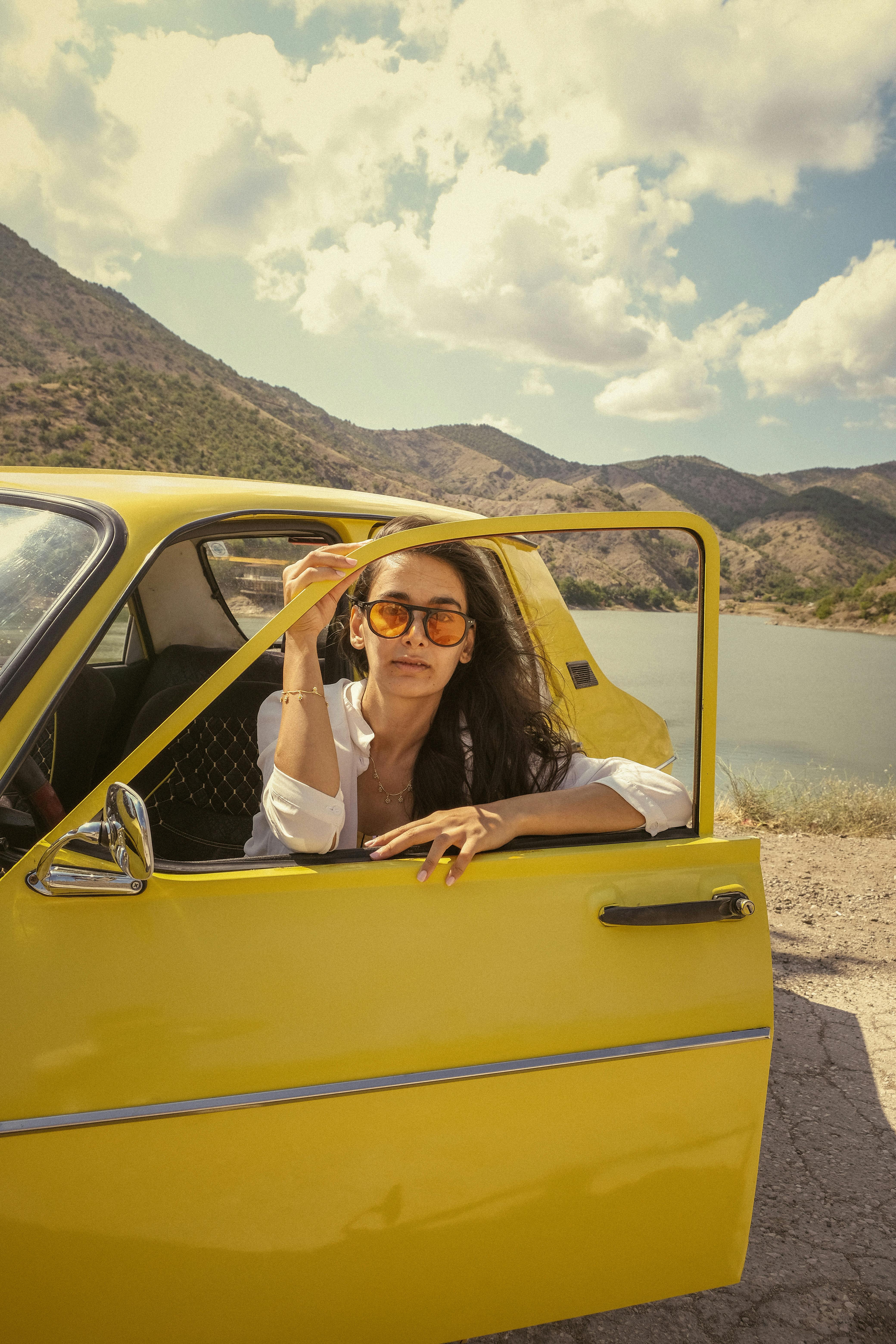 A Woman Sitting in a Yellow Vintage Car · Free Stock Photo