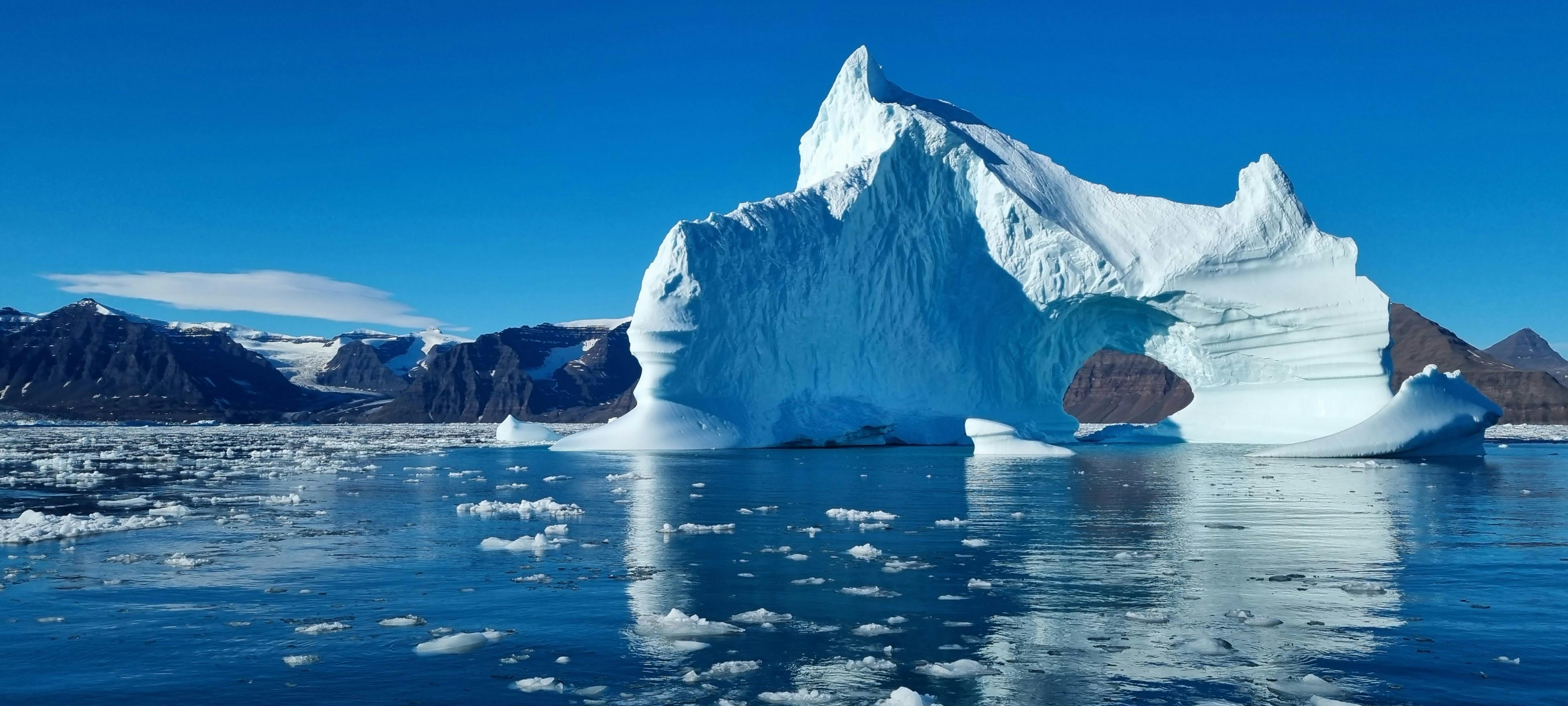 Iceberg on Body of Water Under Blue Sky · Free Stock Photo