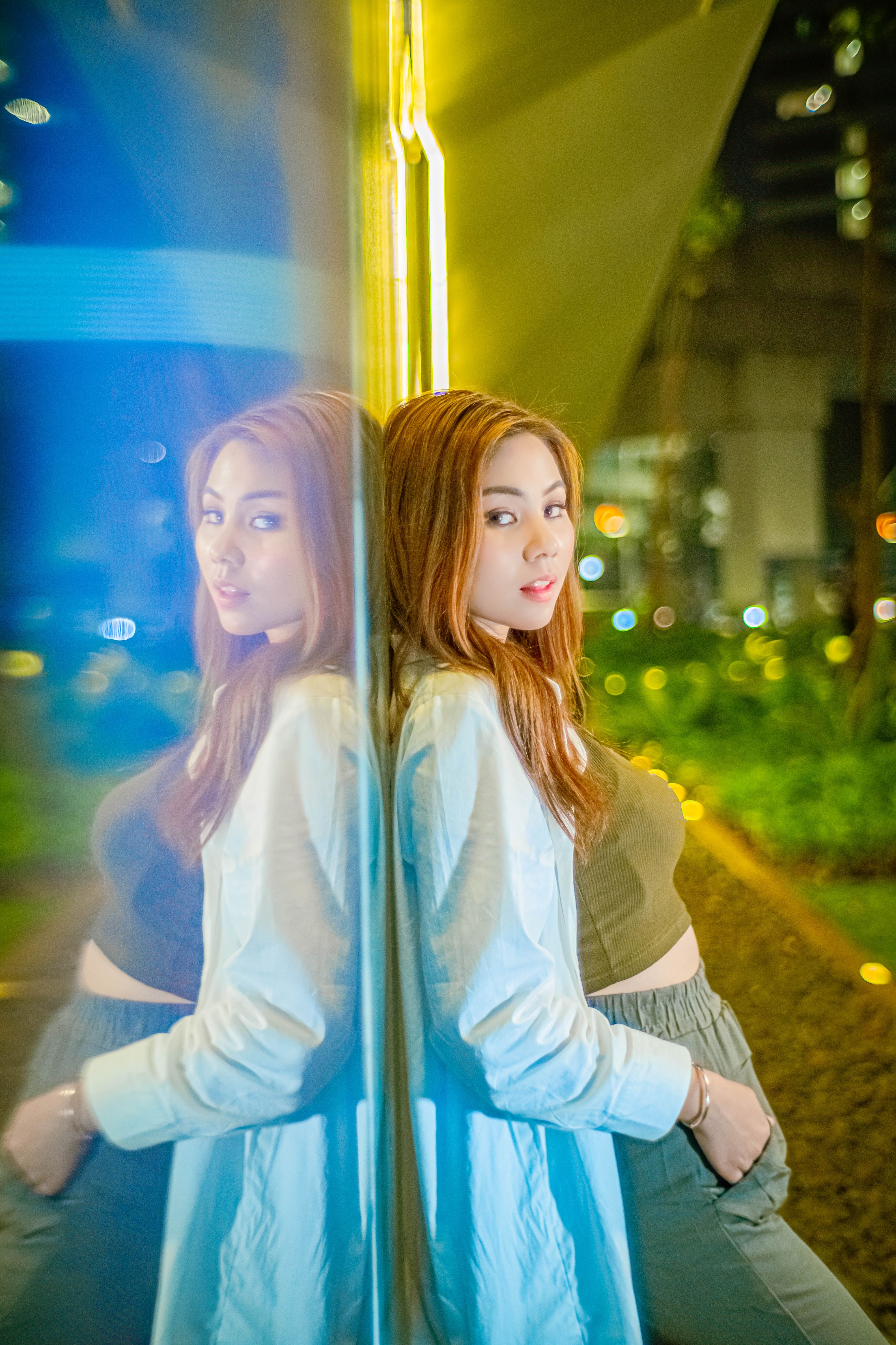 Fashionable Woman Standing in front of a Mirror and Looking over the ...