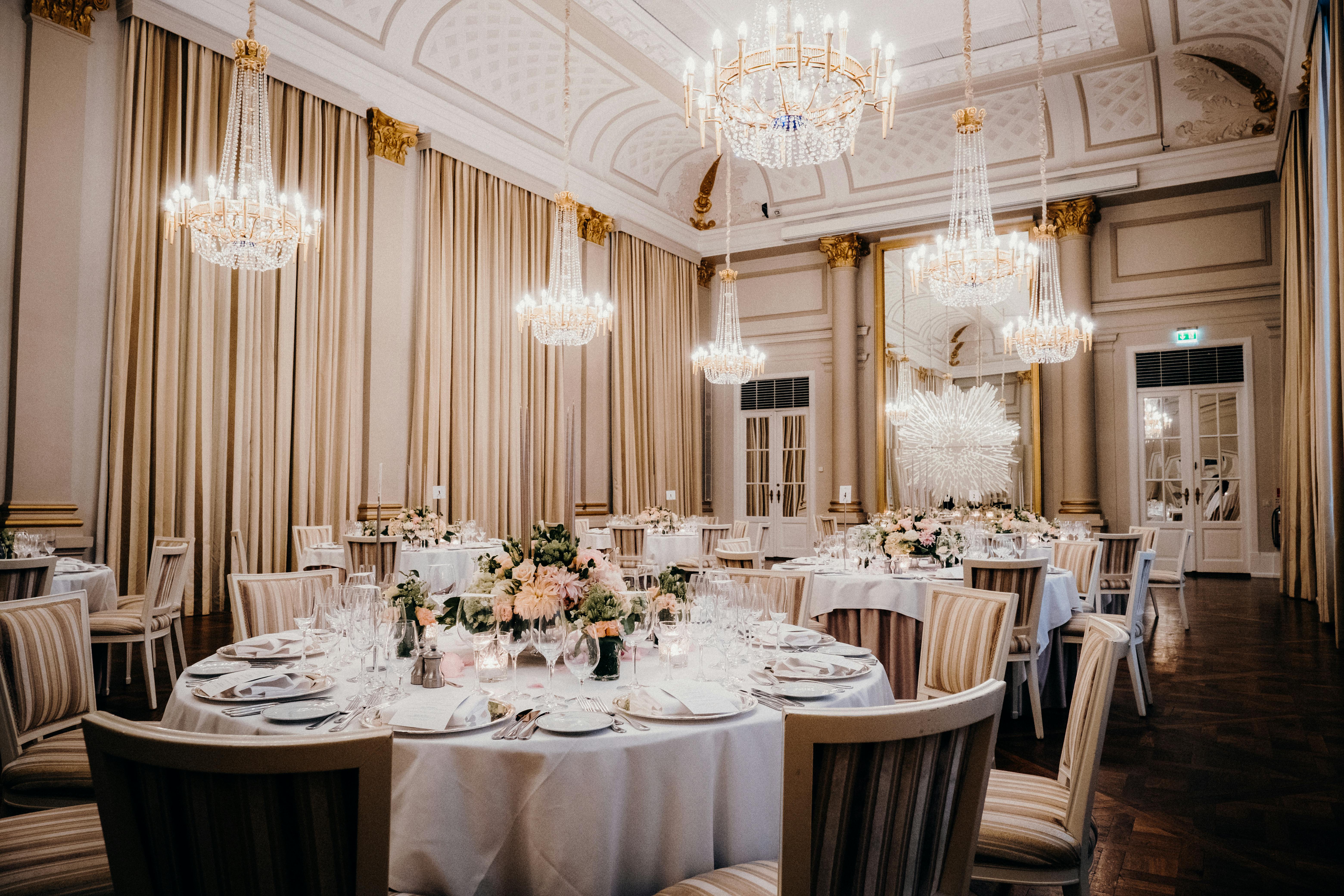 A Table Setting Under the Chandeliers Hanging on Ceiling · Free Stock Photo