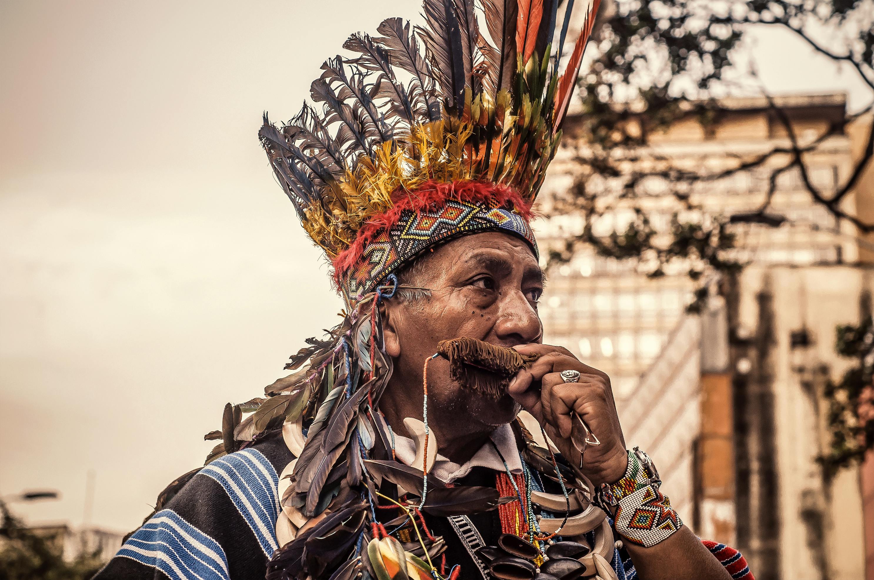 Man with Feathers Wreath Playing Instrument · Free Stock Photo