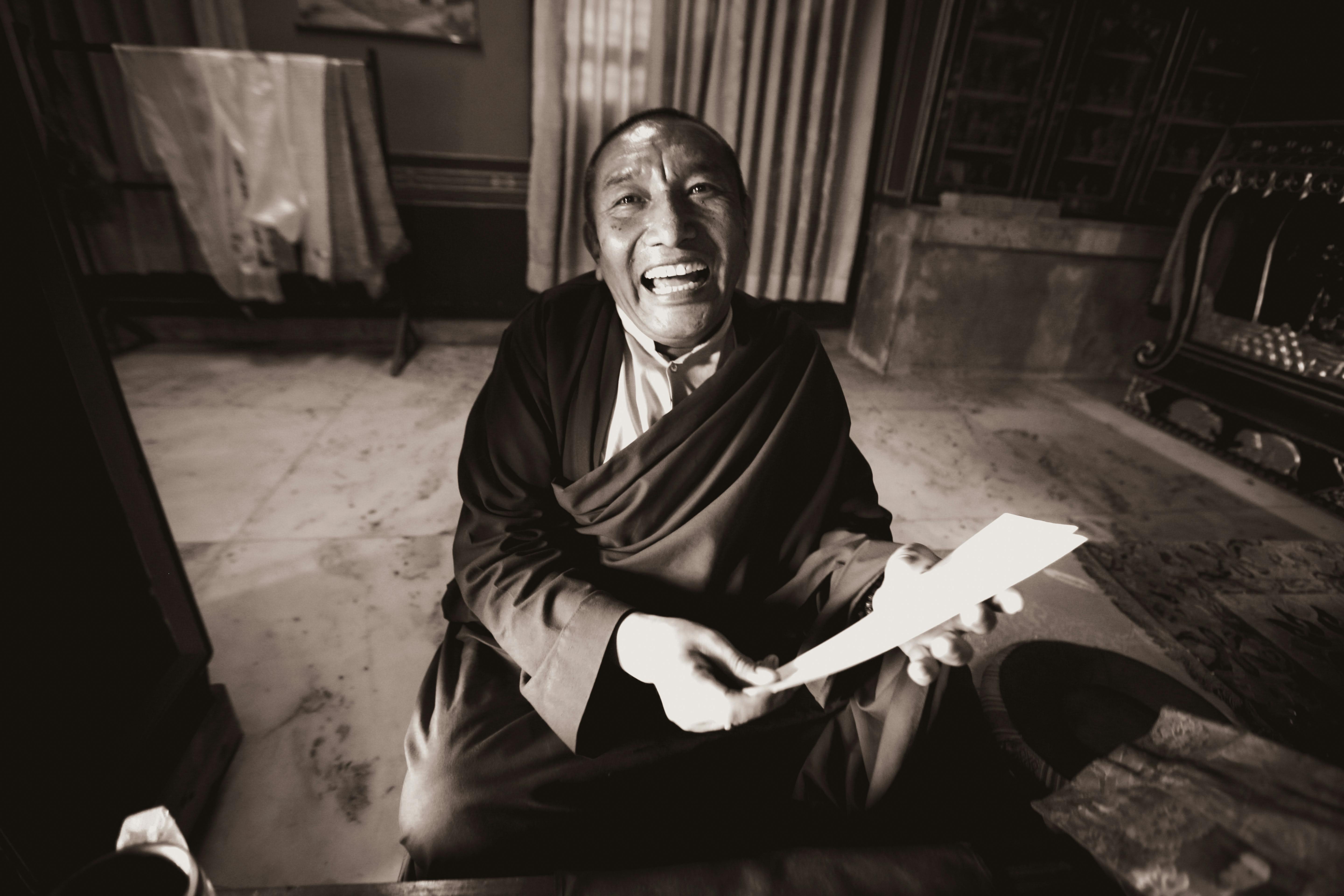A Grayscale Photo of a Person Wearing a Robe Sitting on Floor While ...