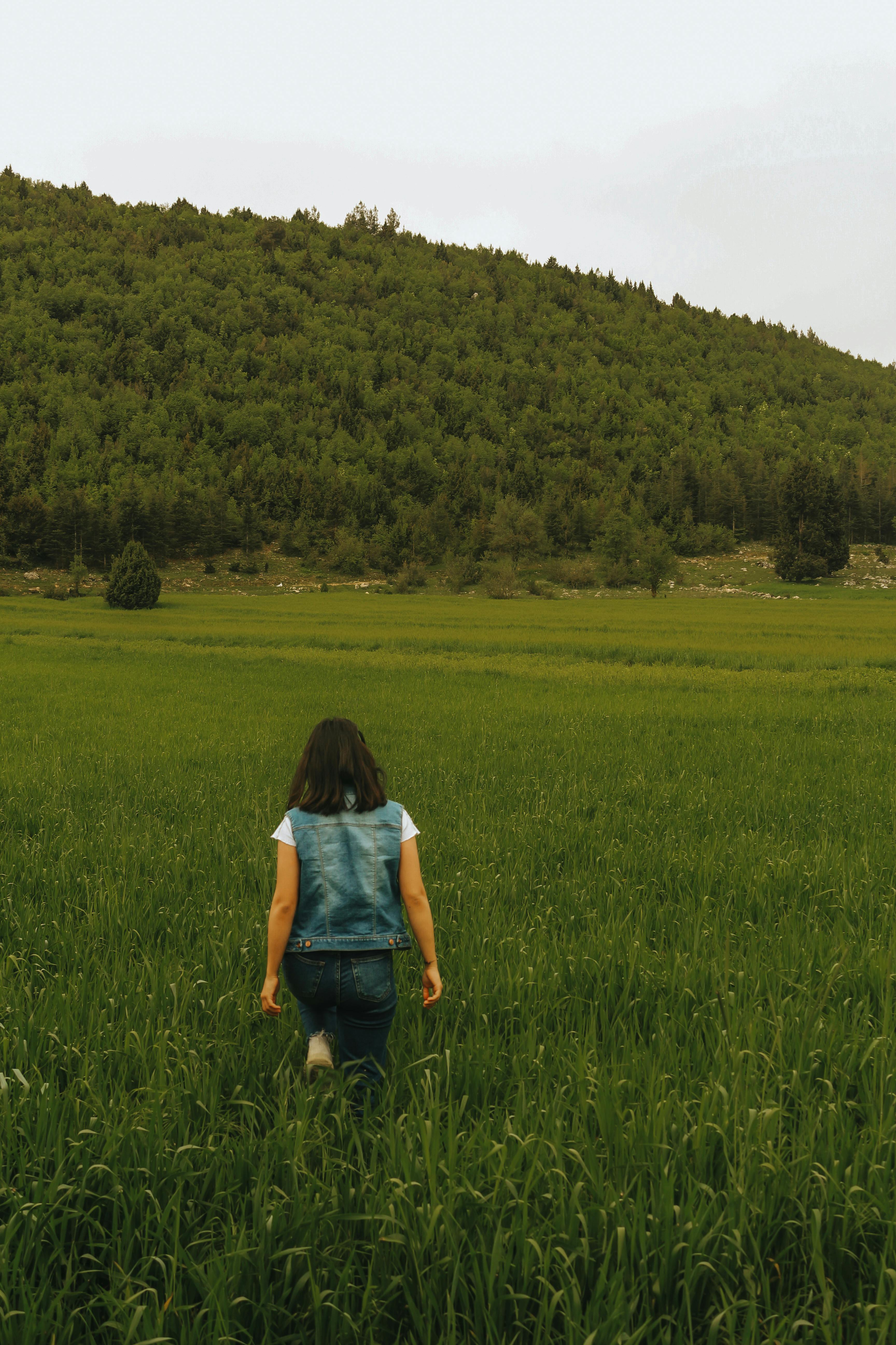 A Woman Walking on a Grass Field · Free Stock Photo