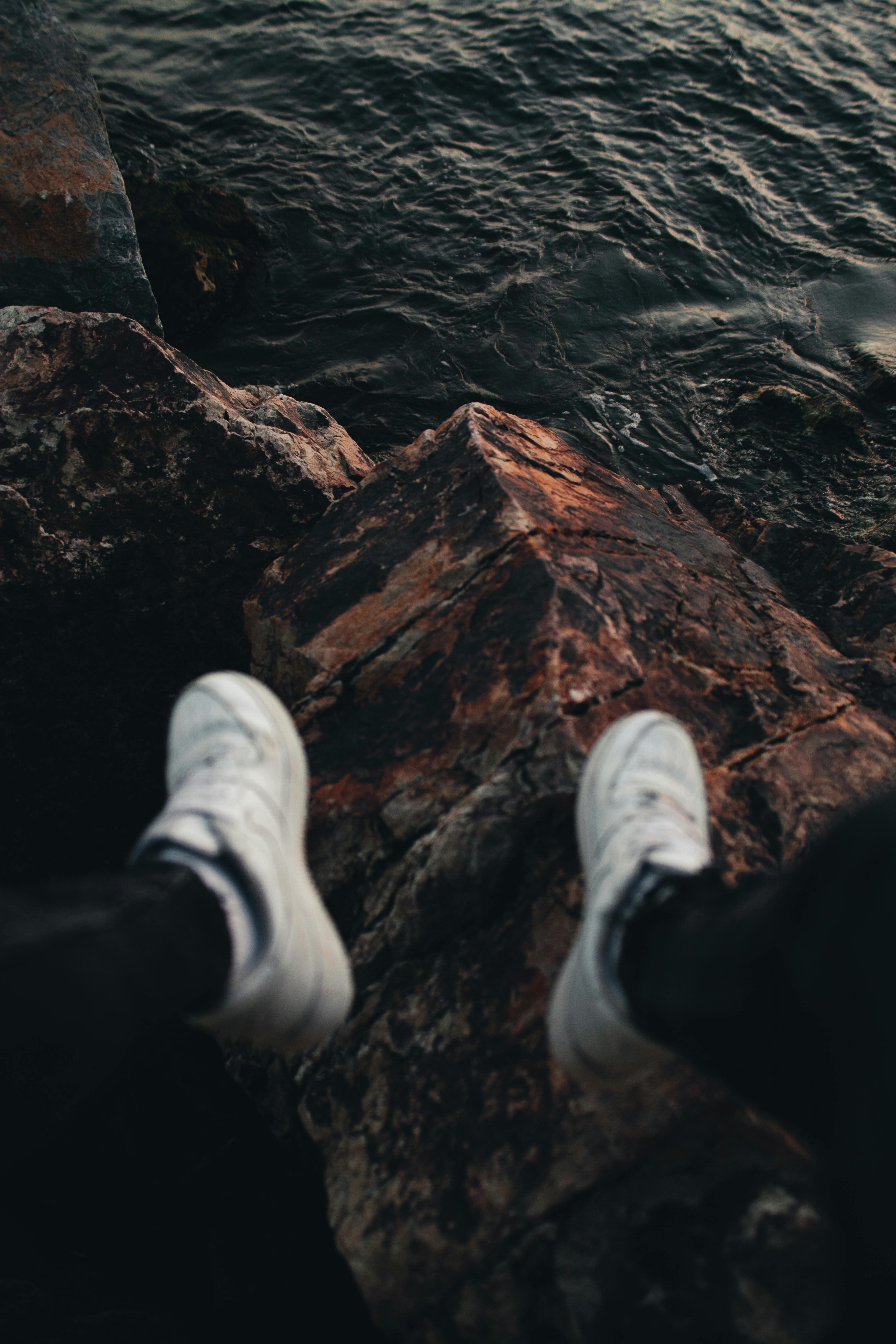 A Person Wearing White Shoes Stepping on the Rock · Free Stock Photo