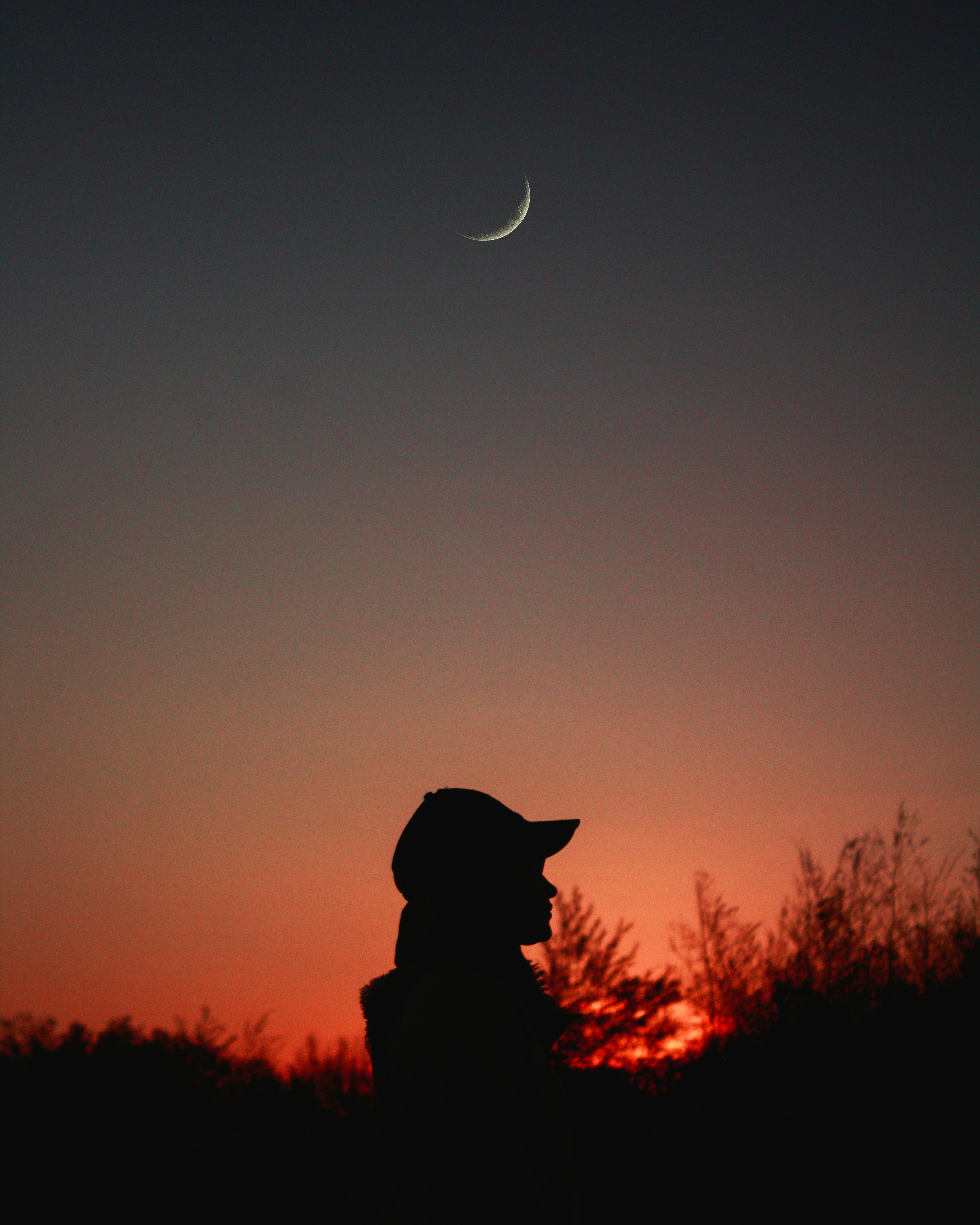 Silhouette of Person Wearing Cap Under Crescent Moon · Free Stock Photo
