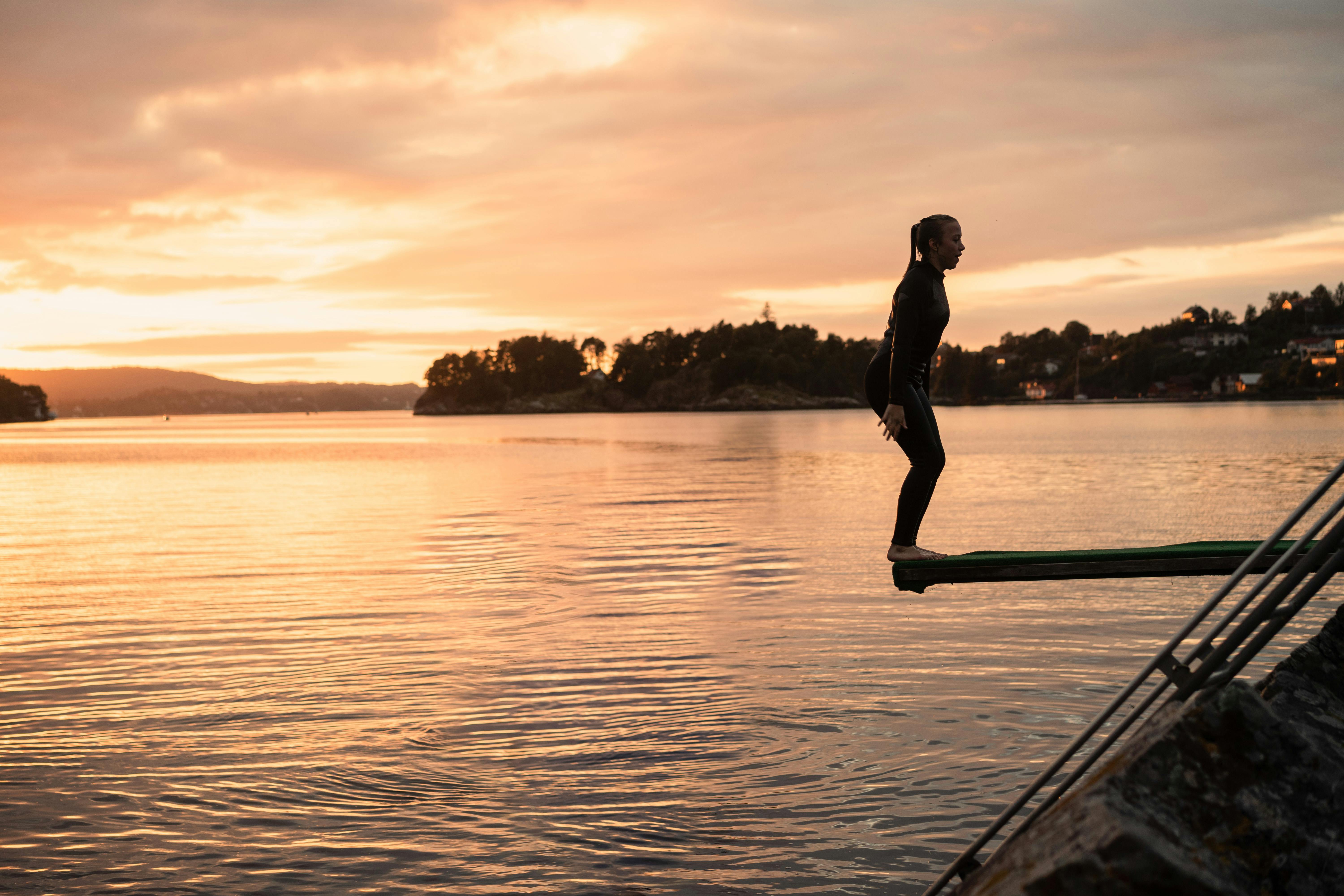 Woman Jumping into a Lake at Sunset · Free Stock Photo