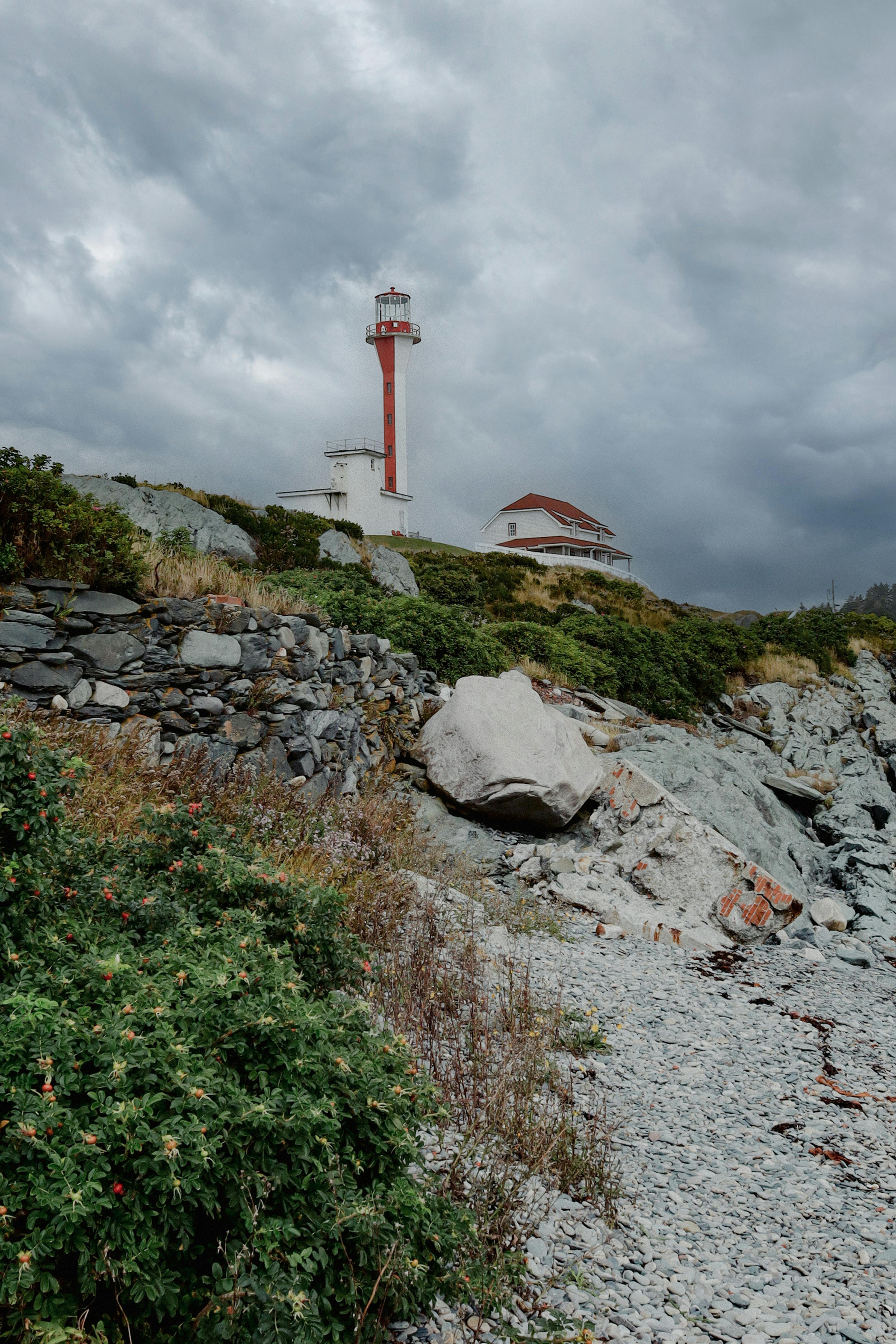 Lighthouse by Rocky Hill Side · Free Stock Photo