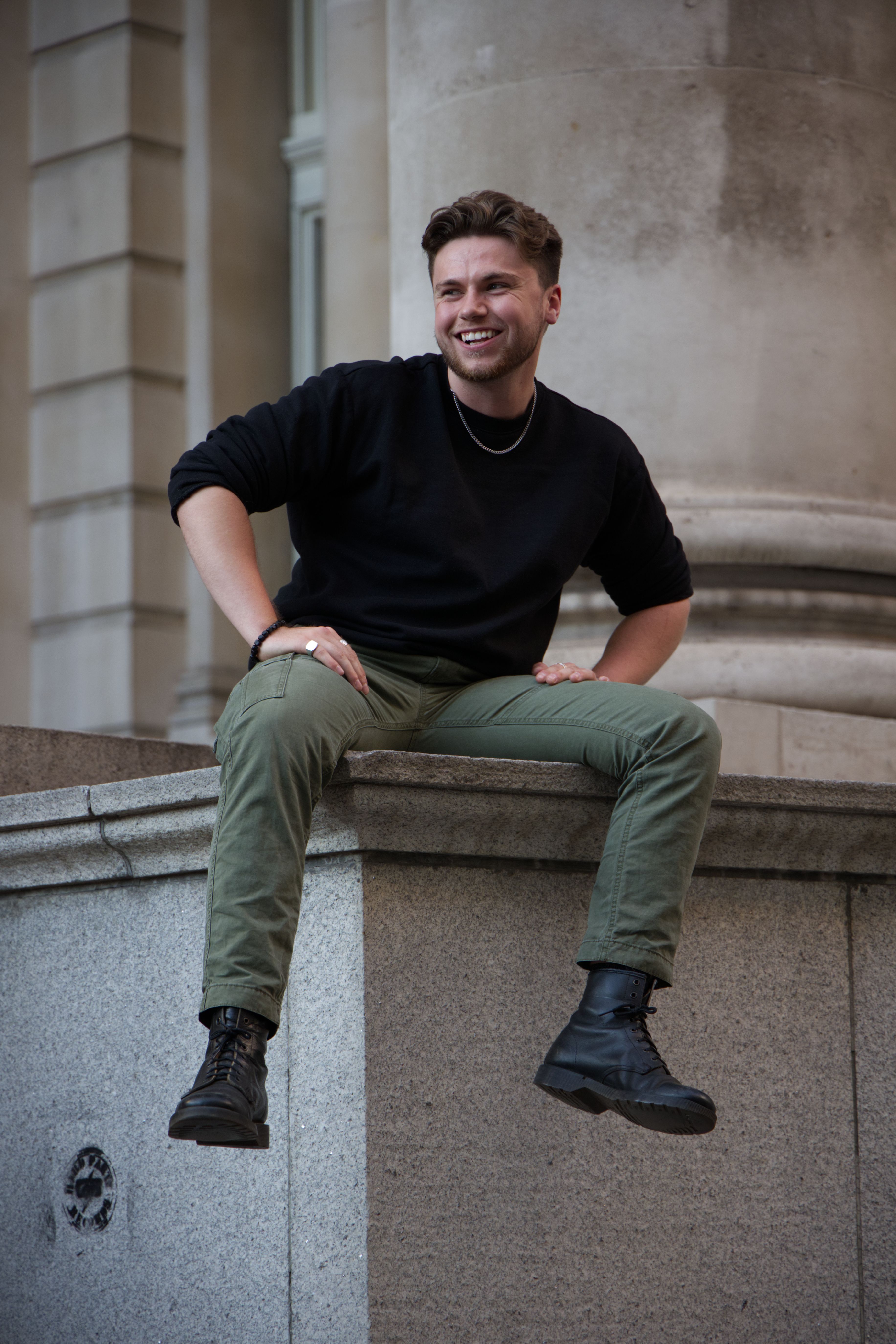 Man Sitting on Wall by Building Entrance · Free Stock Photo