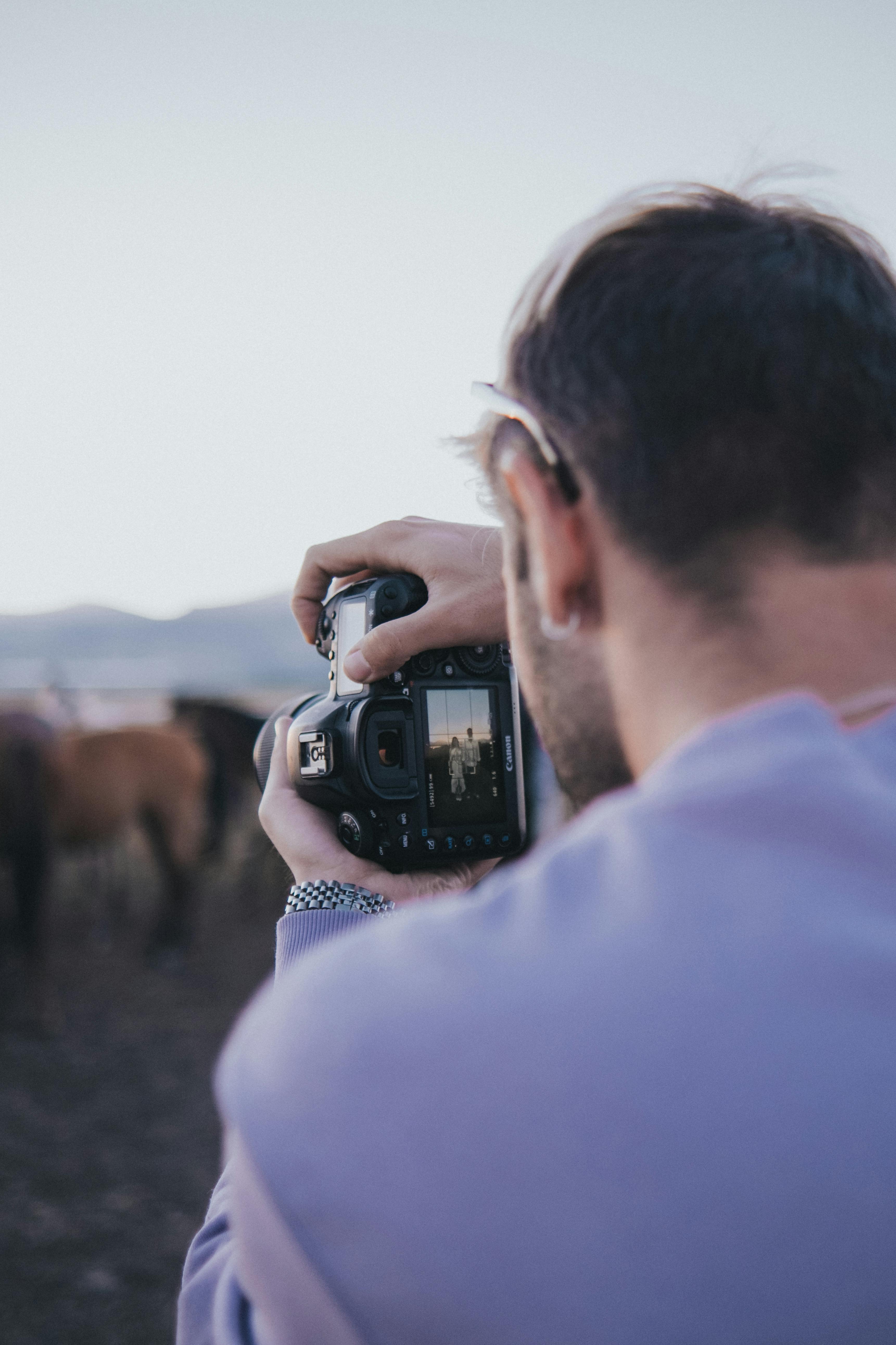 Man Wearing a Purple Sweater Using a DSLR Camera · Free Stock Photo