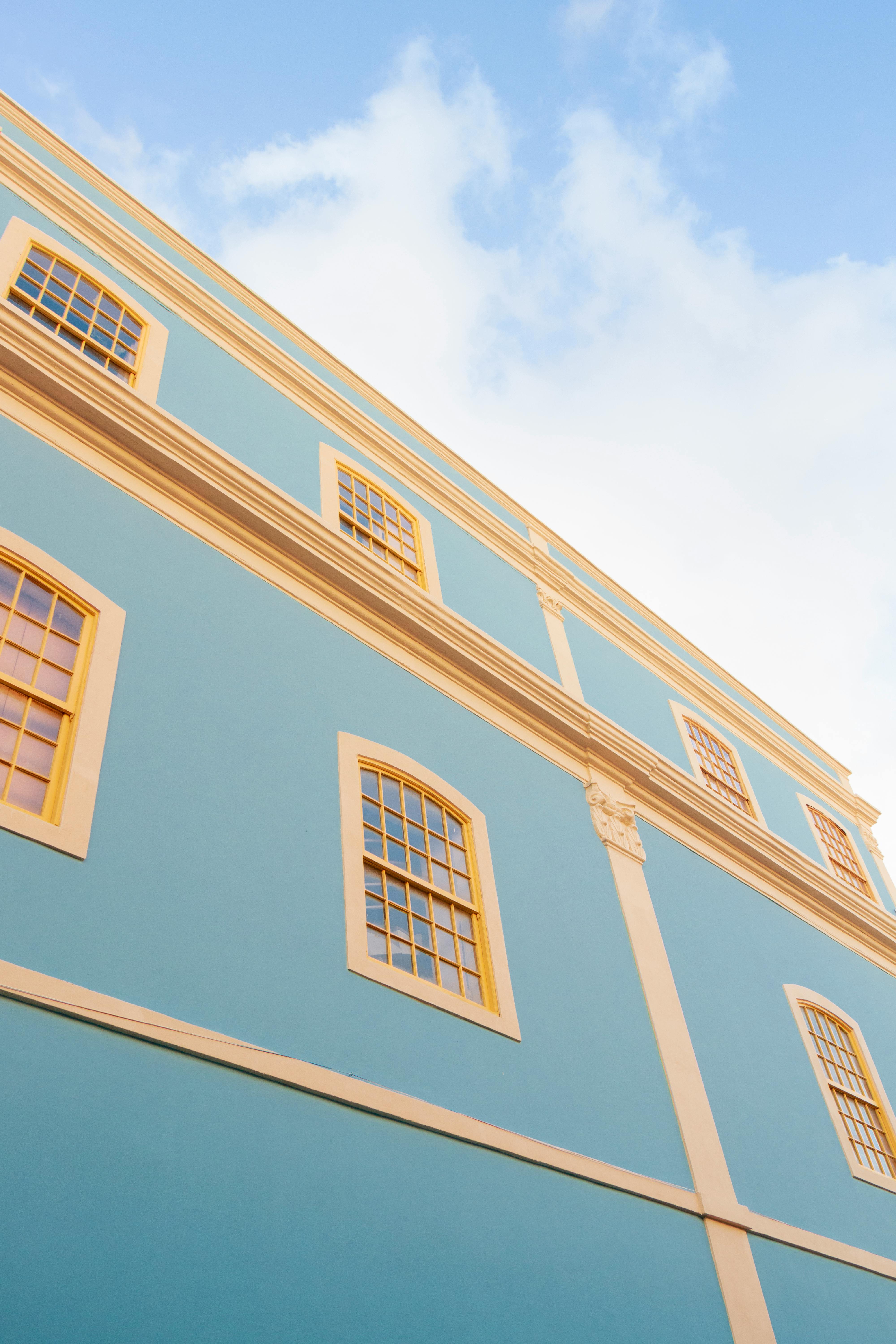 Top of Vibrant Yellow Building Against Blu · Free Stock Photo