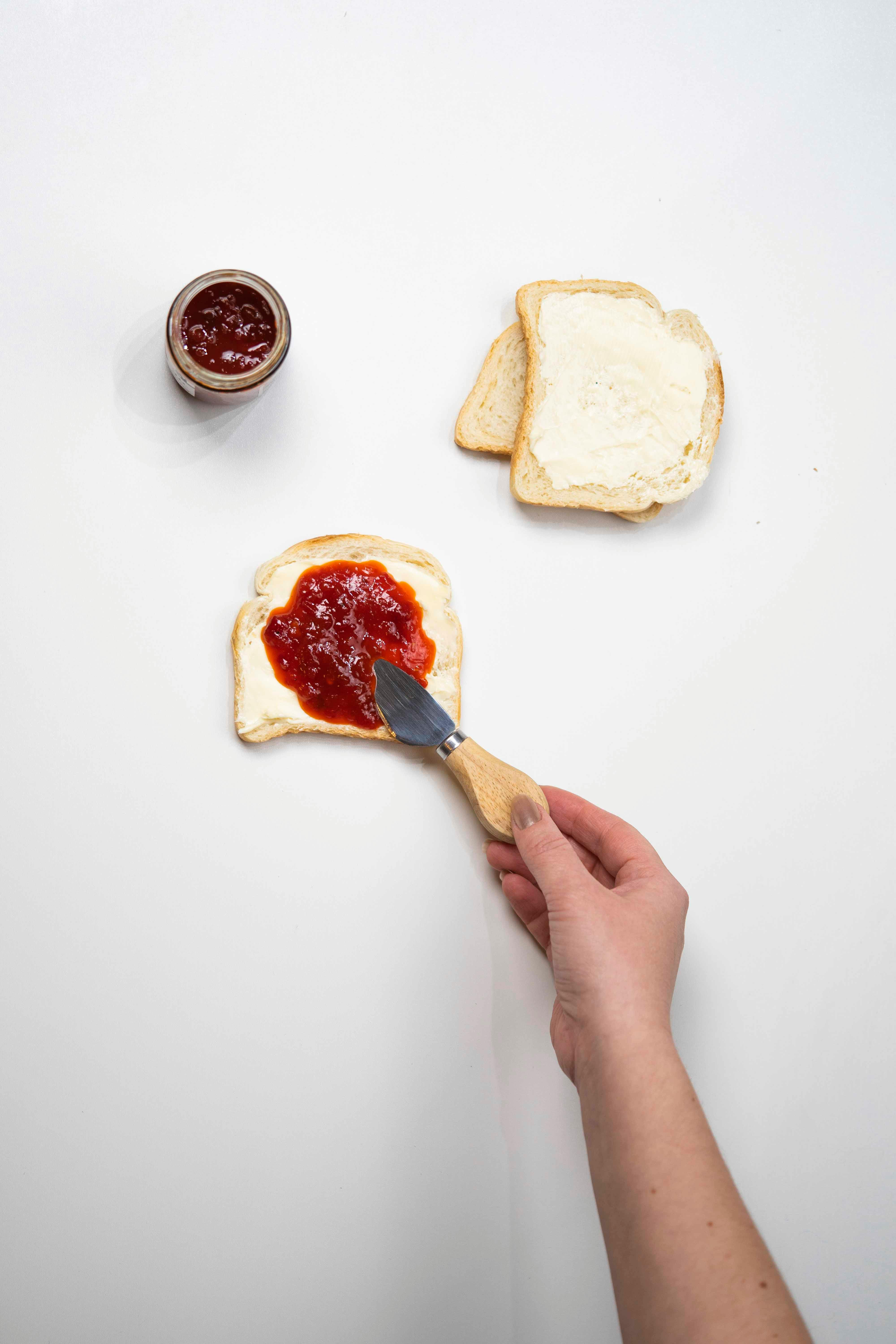 A Hand Spreading the Jam on the Sandwich · Free Stock Photo