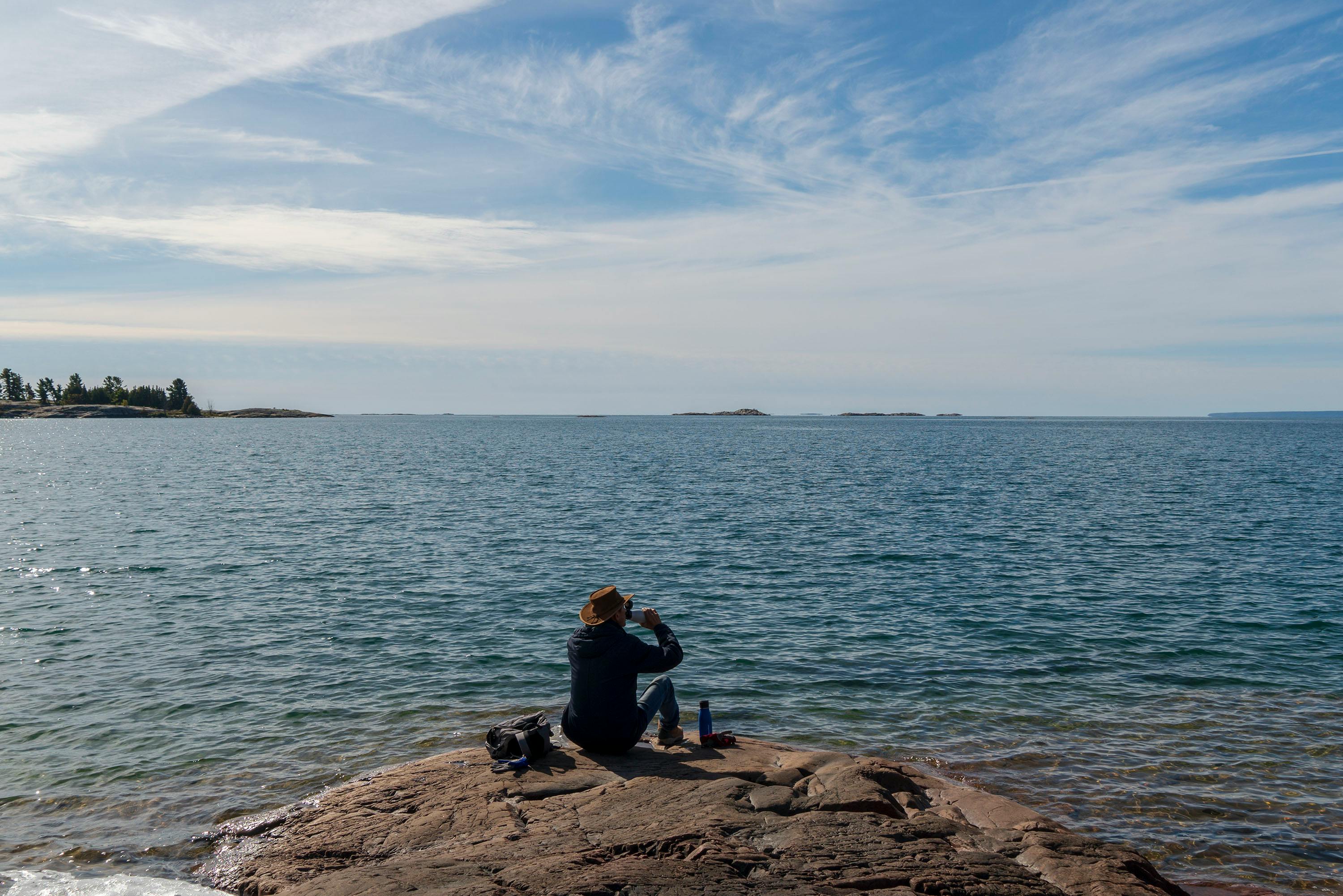 A Person Sitting on the Rock Near the Sea · Free Stock Photo