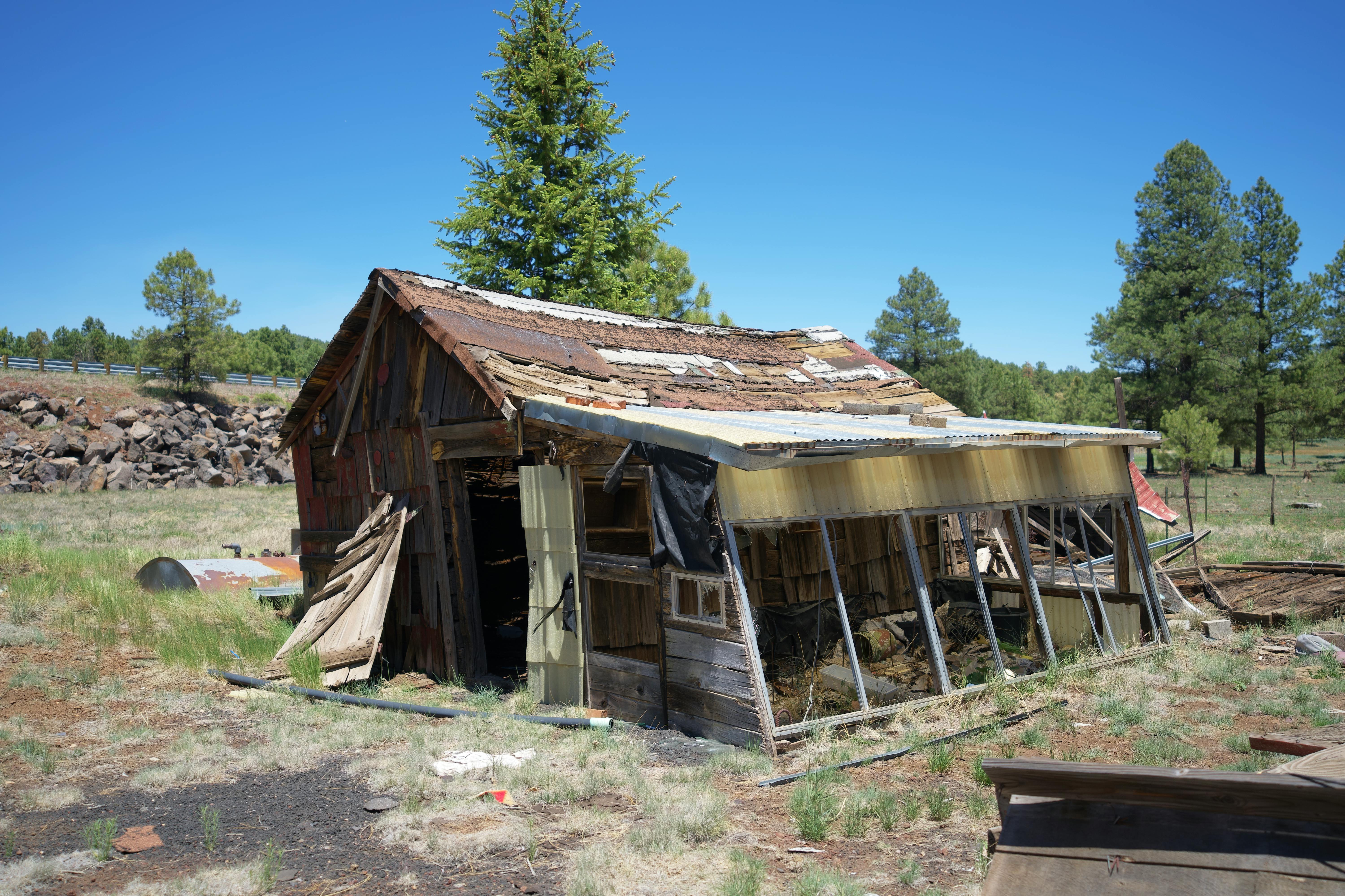 Abandoned, Damaged Wooden Cabin on a Field · Free Stock Photo