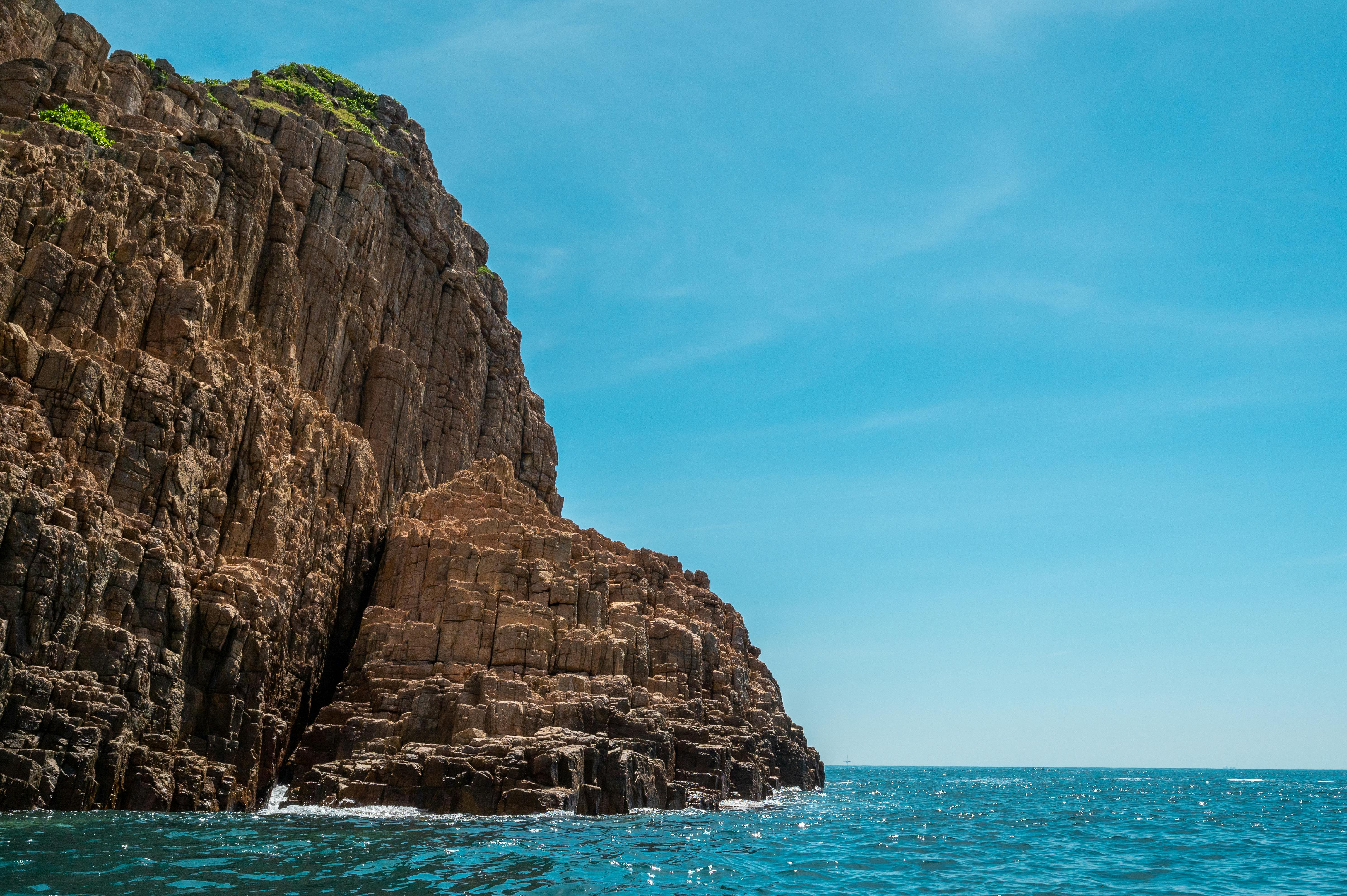 Brown Rock Formation on Sea Under Blue Sky · Free Stock Photo