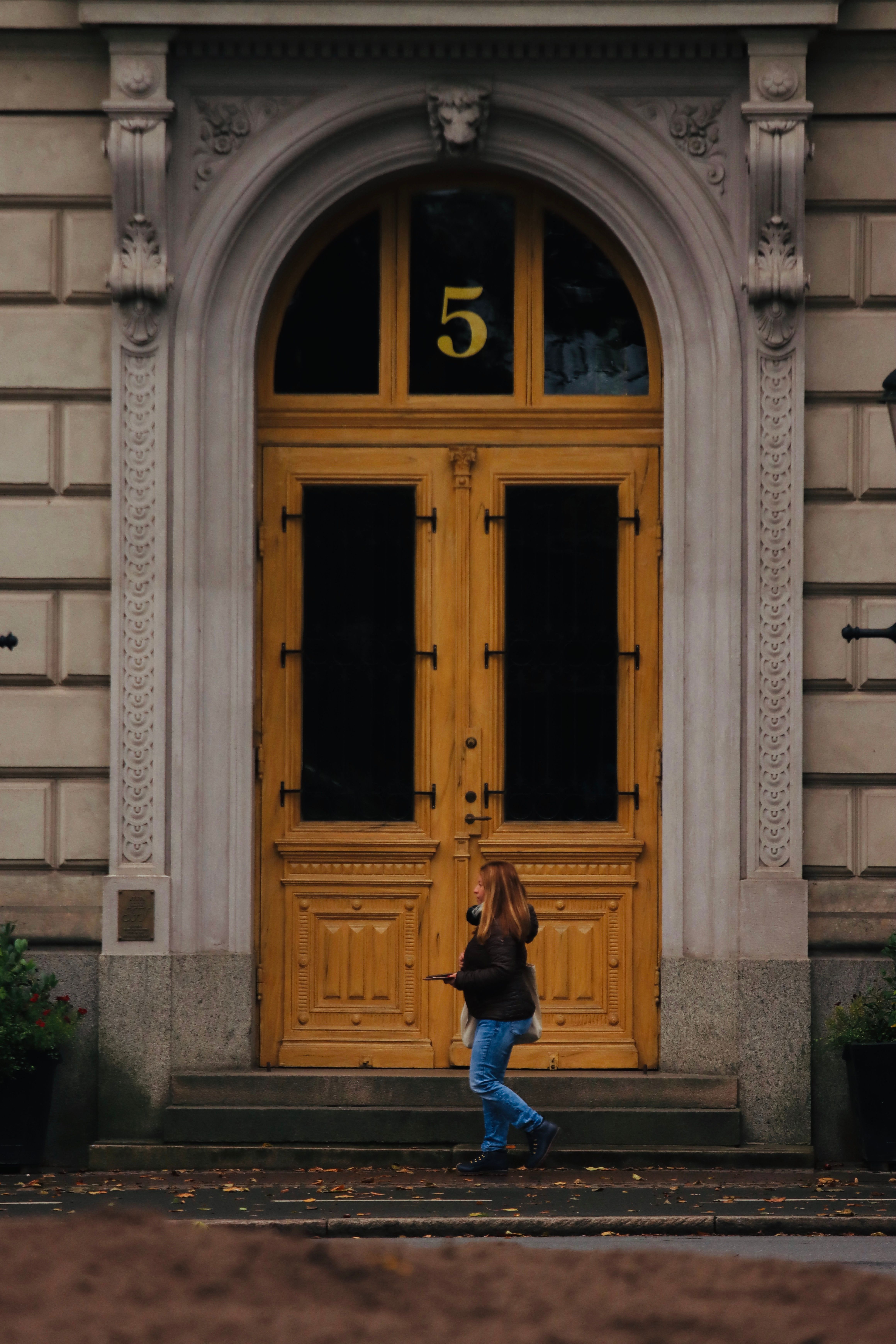 A Woman Walking near the Huge Wooden Door · Free Stock Photo