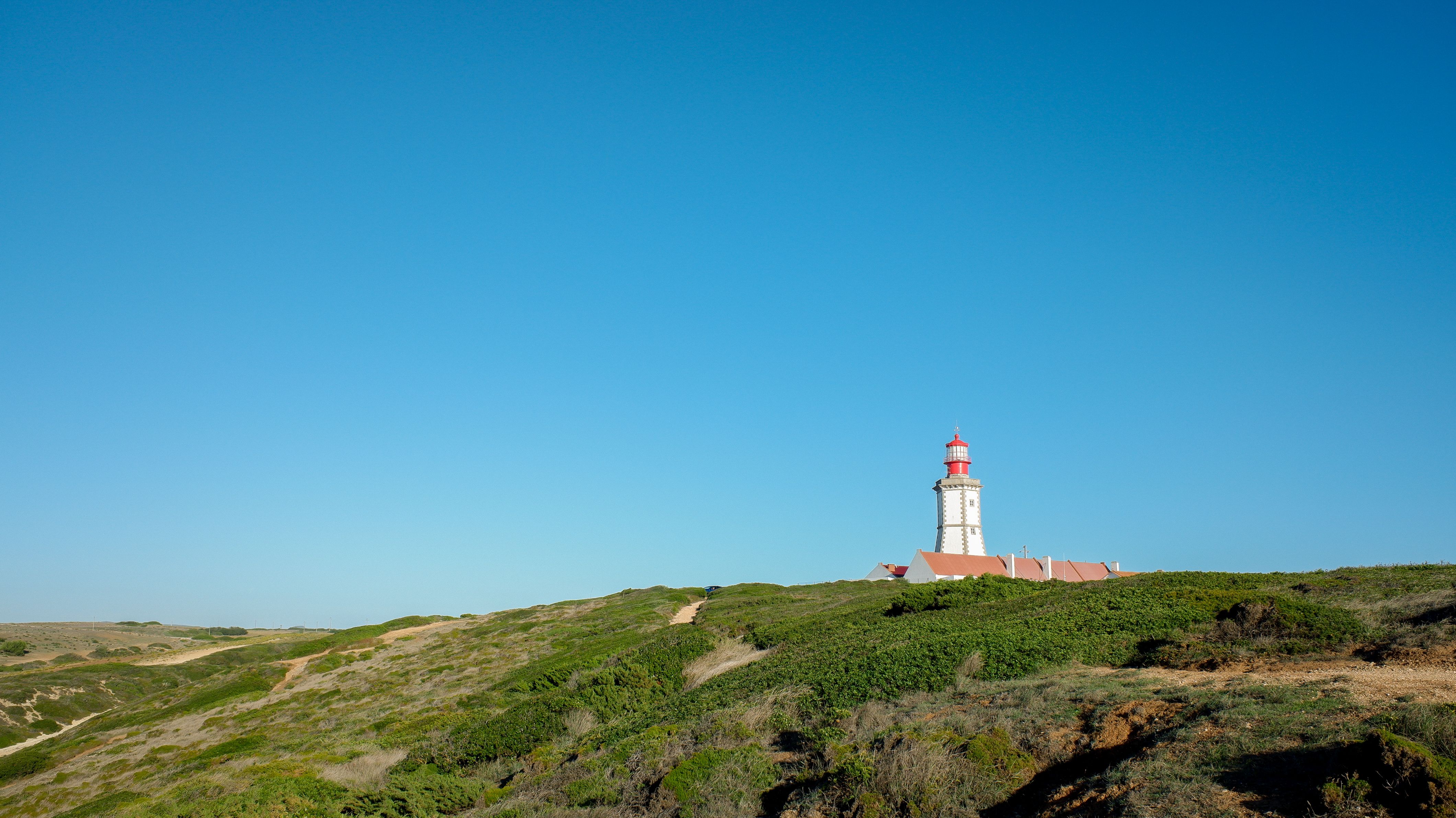 A Lighthouse on Green Grass Under a Clear Blue Sky · Free Stock Photo
