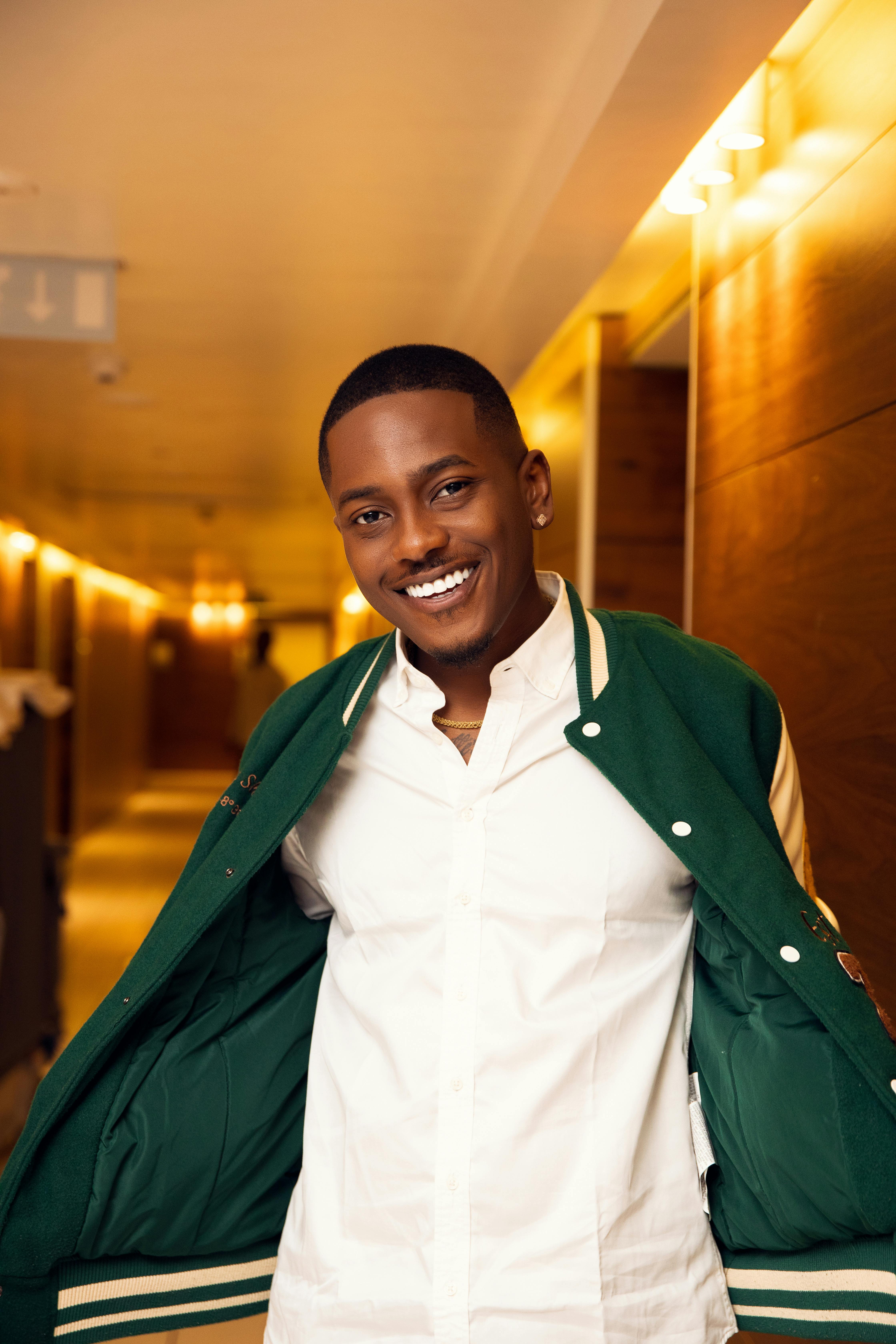 Man Wearing Green Jacket Standing at a Hallway · Free Stock Photo