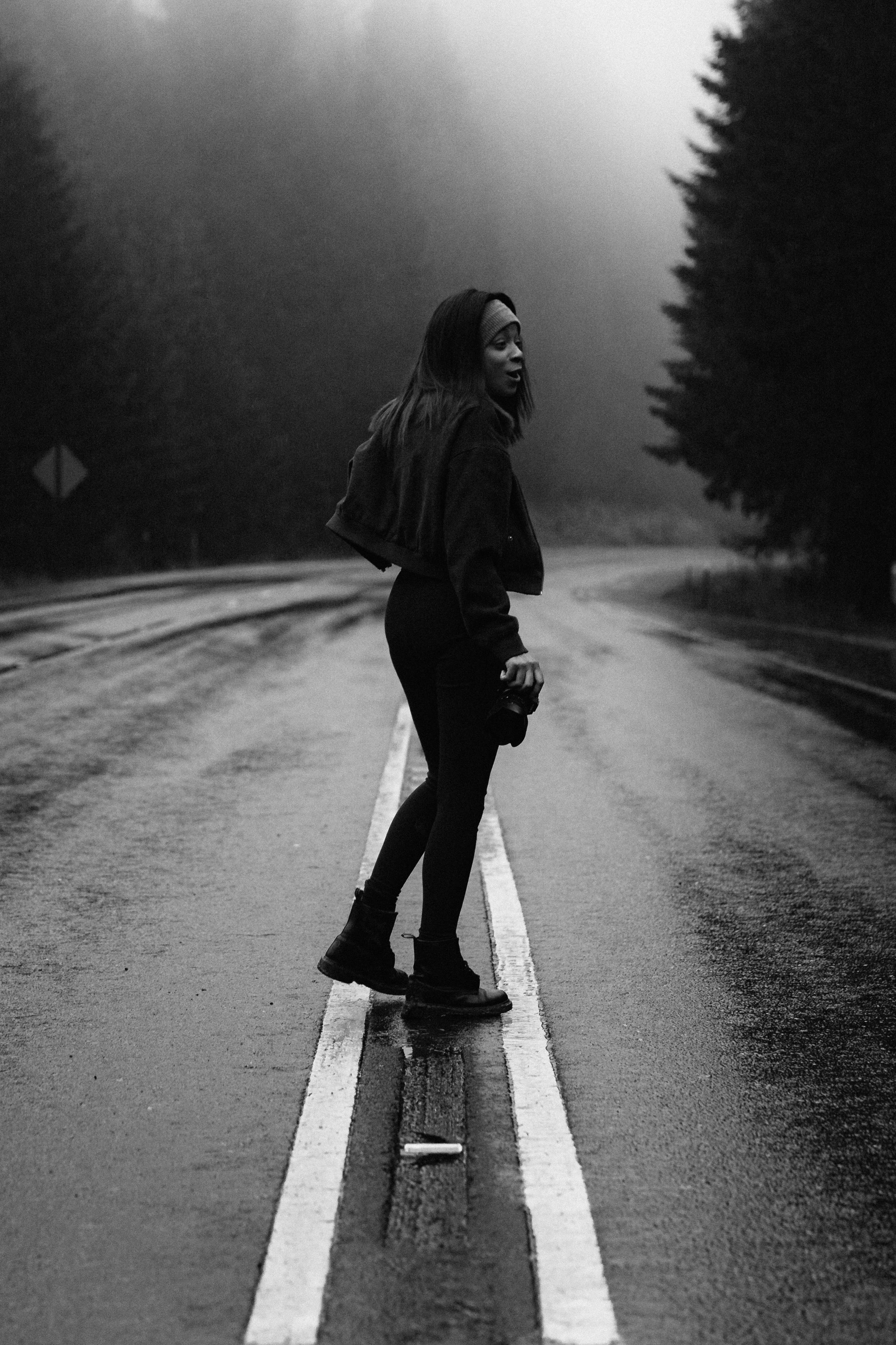 Grayscale Photo of a Woman Standing on the Road · Free Stock Photo