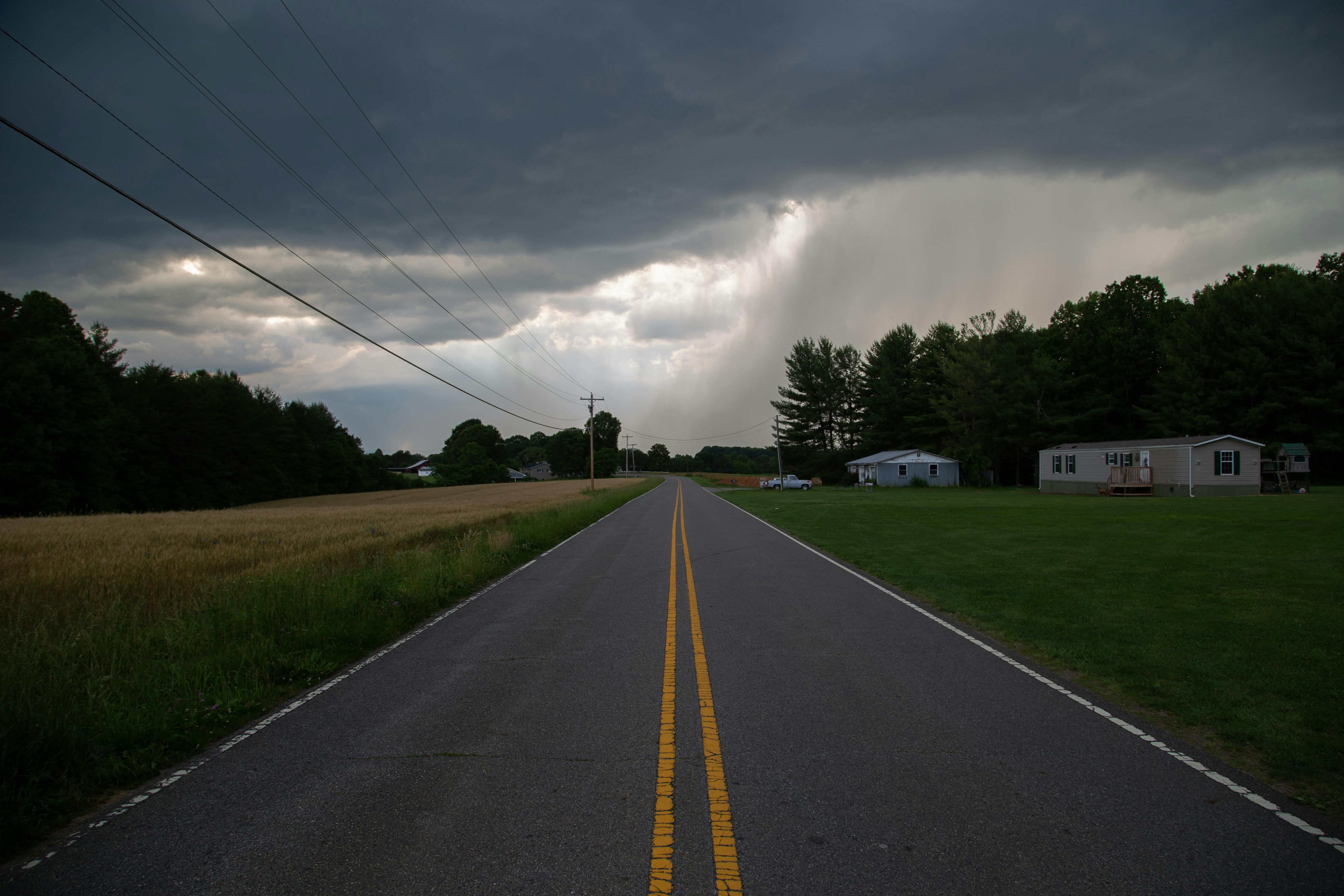 Gray Asphalt Road Between Green Grass Field Under White Clouds and Blue Sky · Free Stock Photo