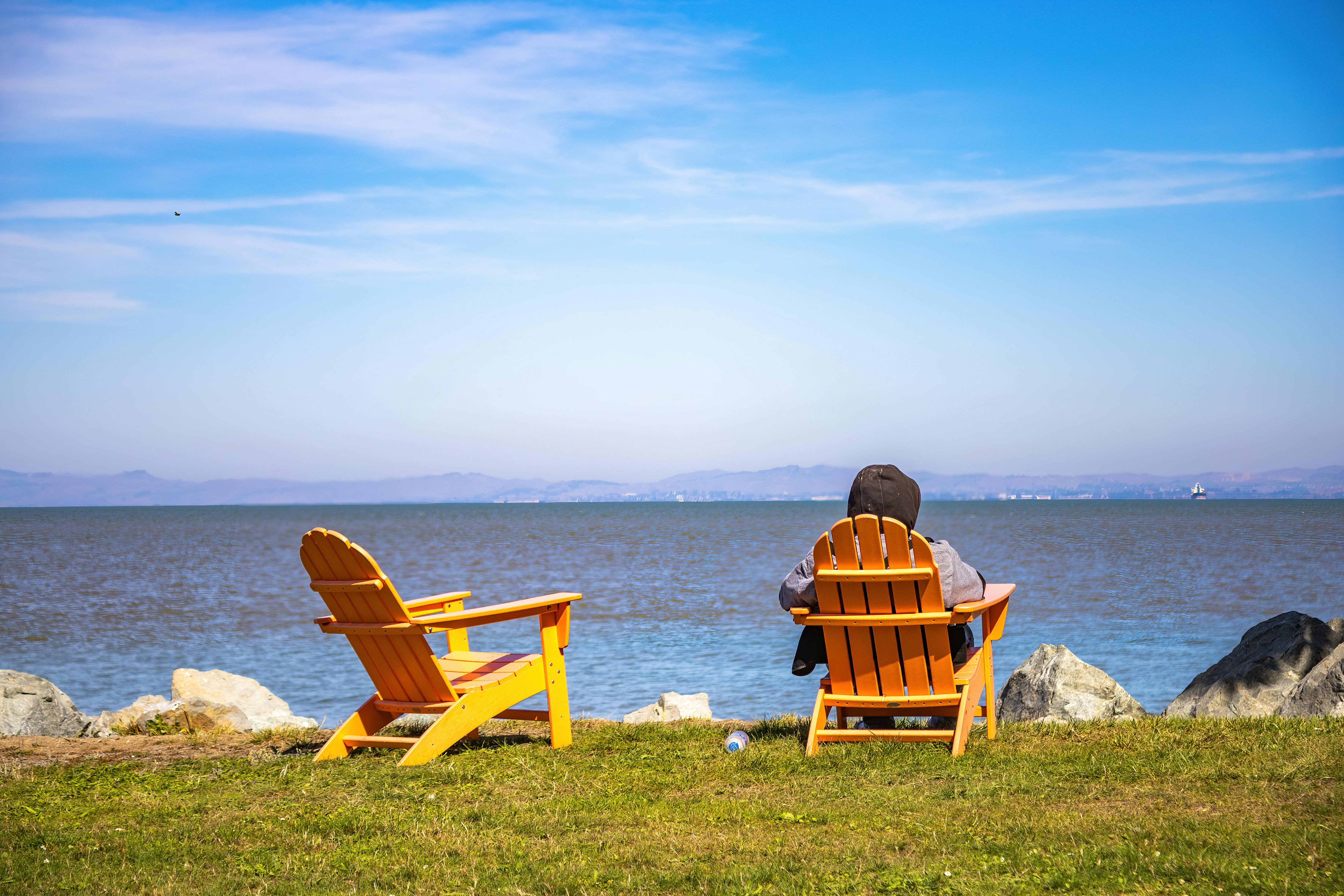 Person Sitting on a Wooden Chair near Sea · Free Stock Photo