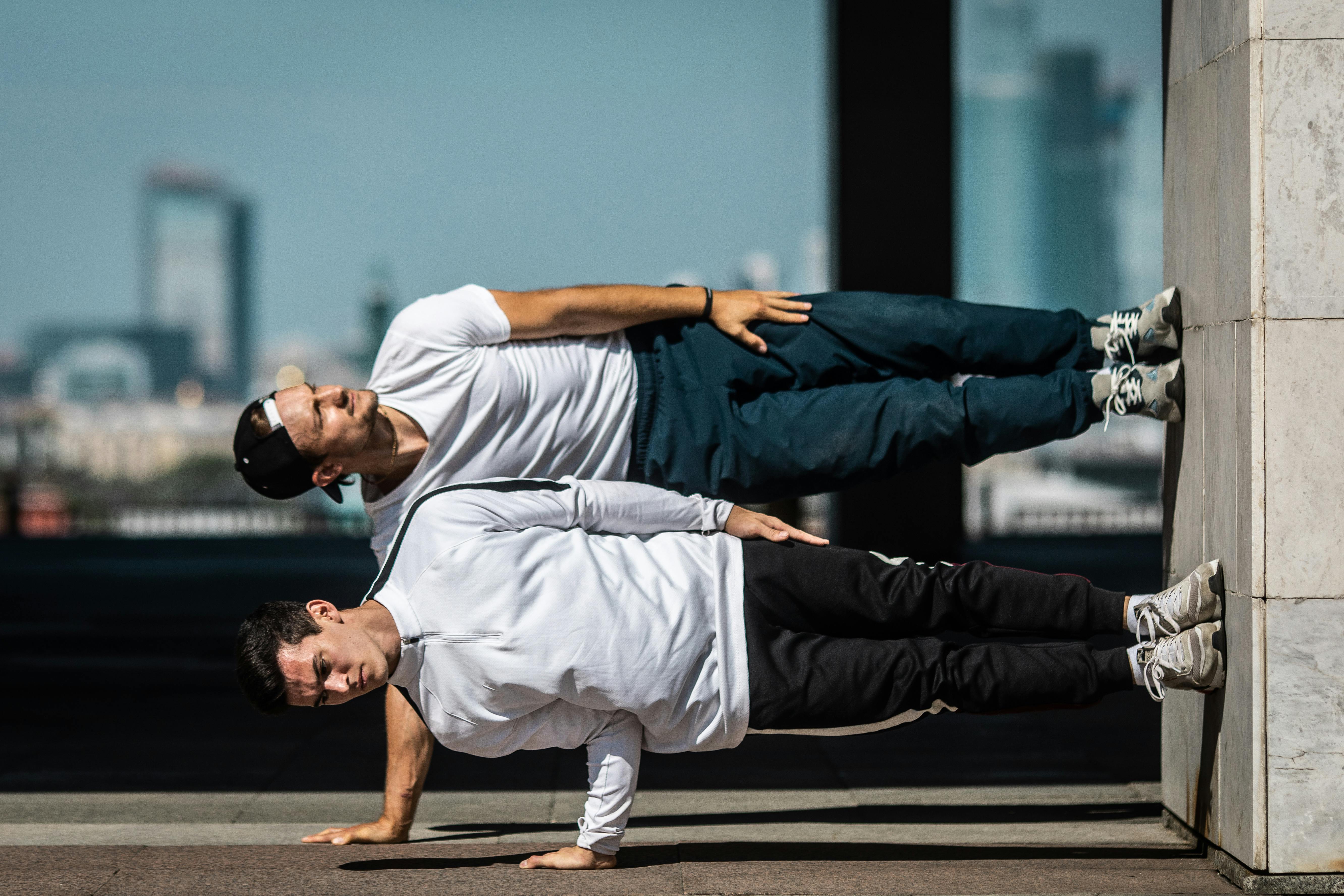 Men Practising One Hand Plank on a Rooftop · Free Stock Photo
