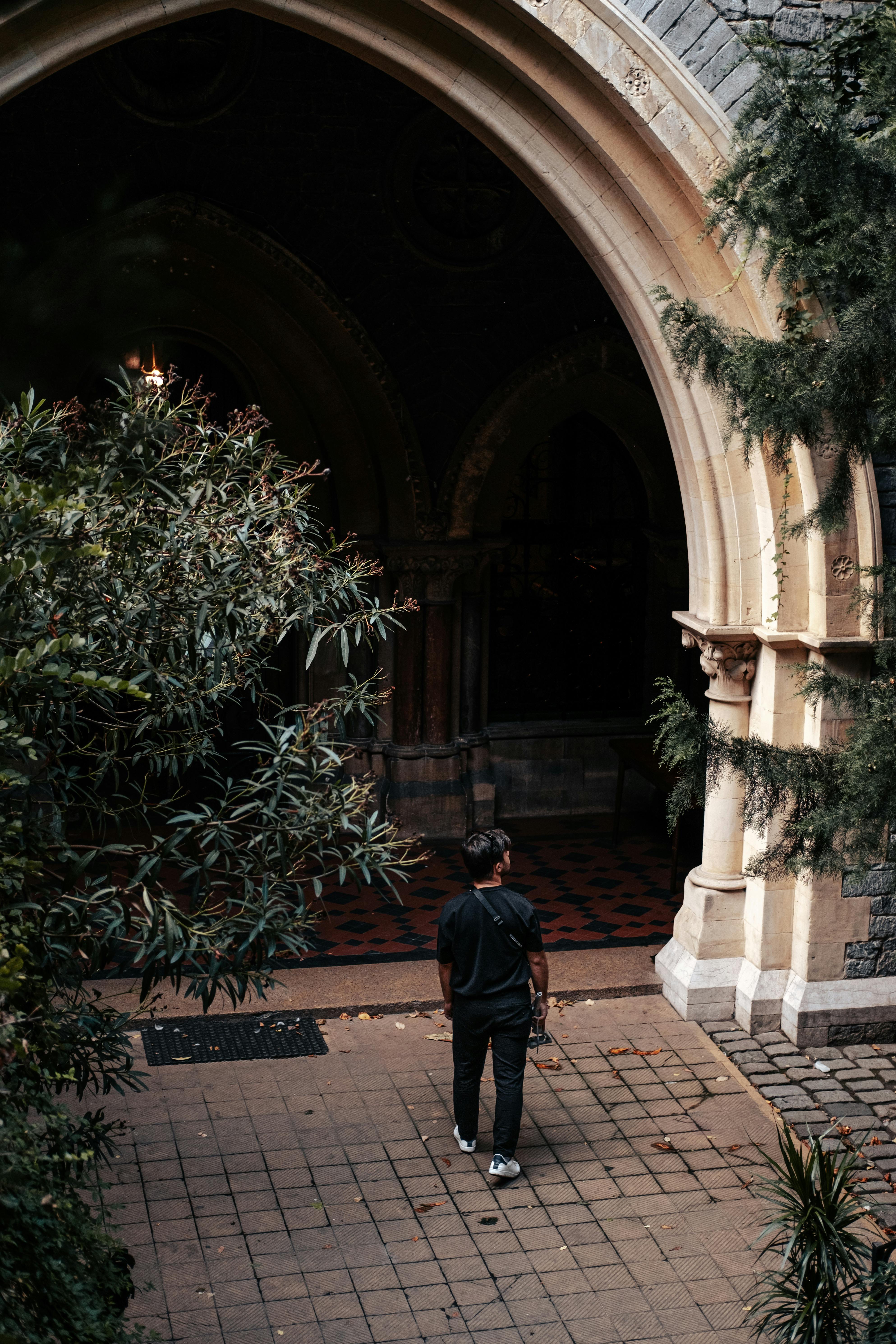 Man Standing under Monumental Building Entrance · Free Stock Photo