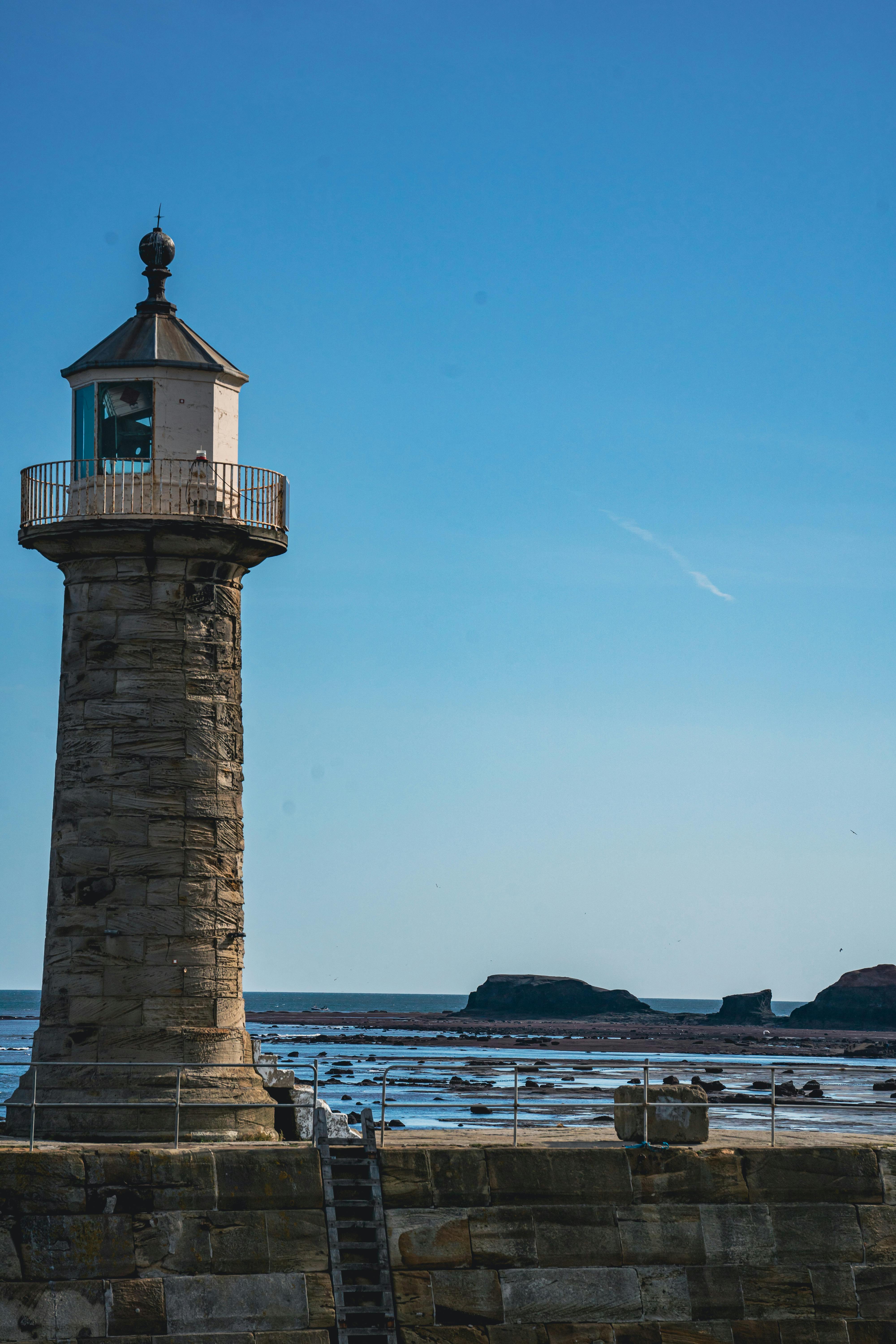 A Lighthouse on a Concrete Dock Under Blue Sky · Free Stock Photo