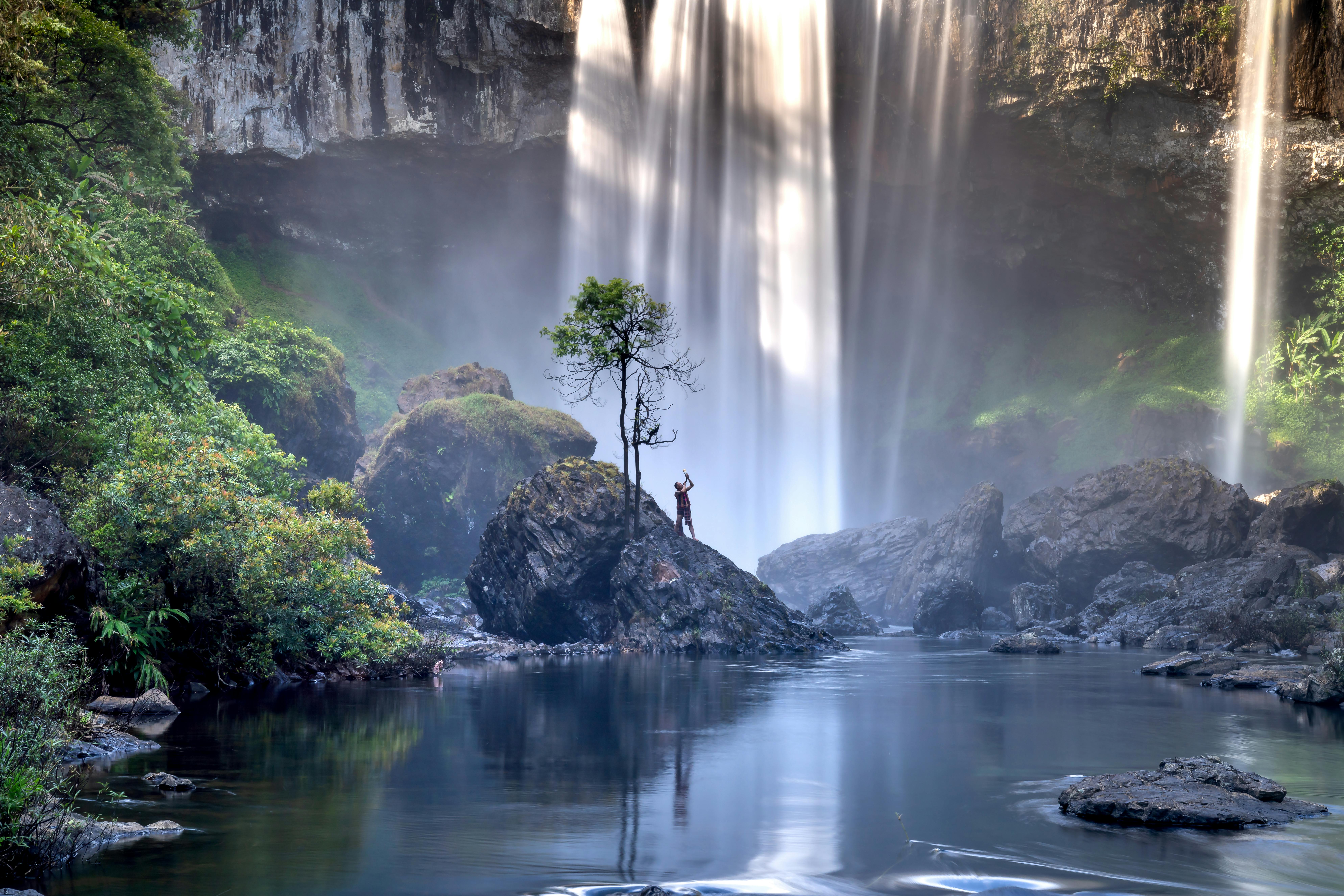 Person Standing on a Rock Near Waterfalls · Free Stock Photo
