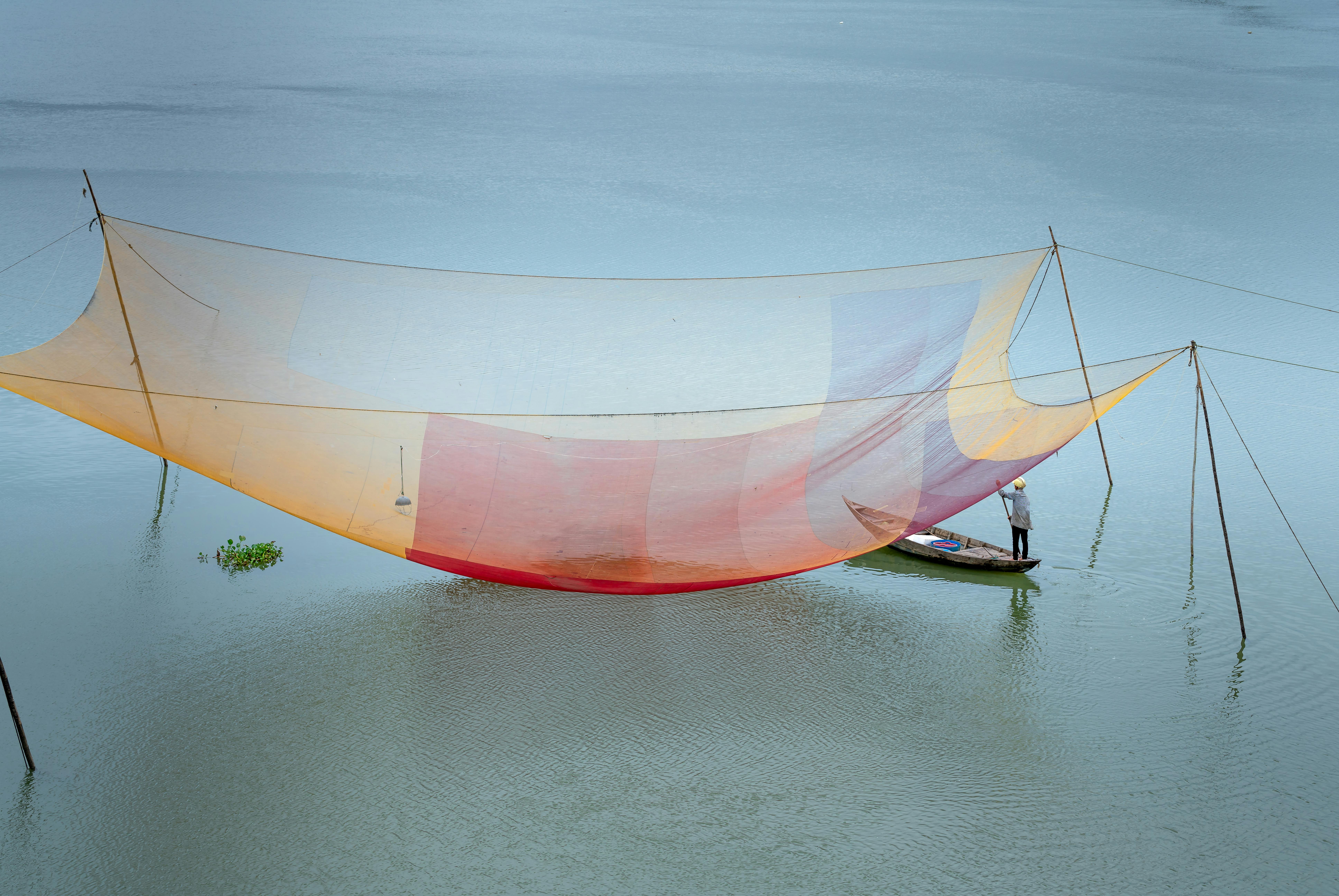 Person Standing on Boat Beside a Fishing Net · Free Stock Photo
