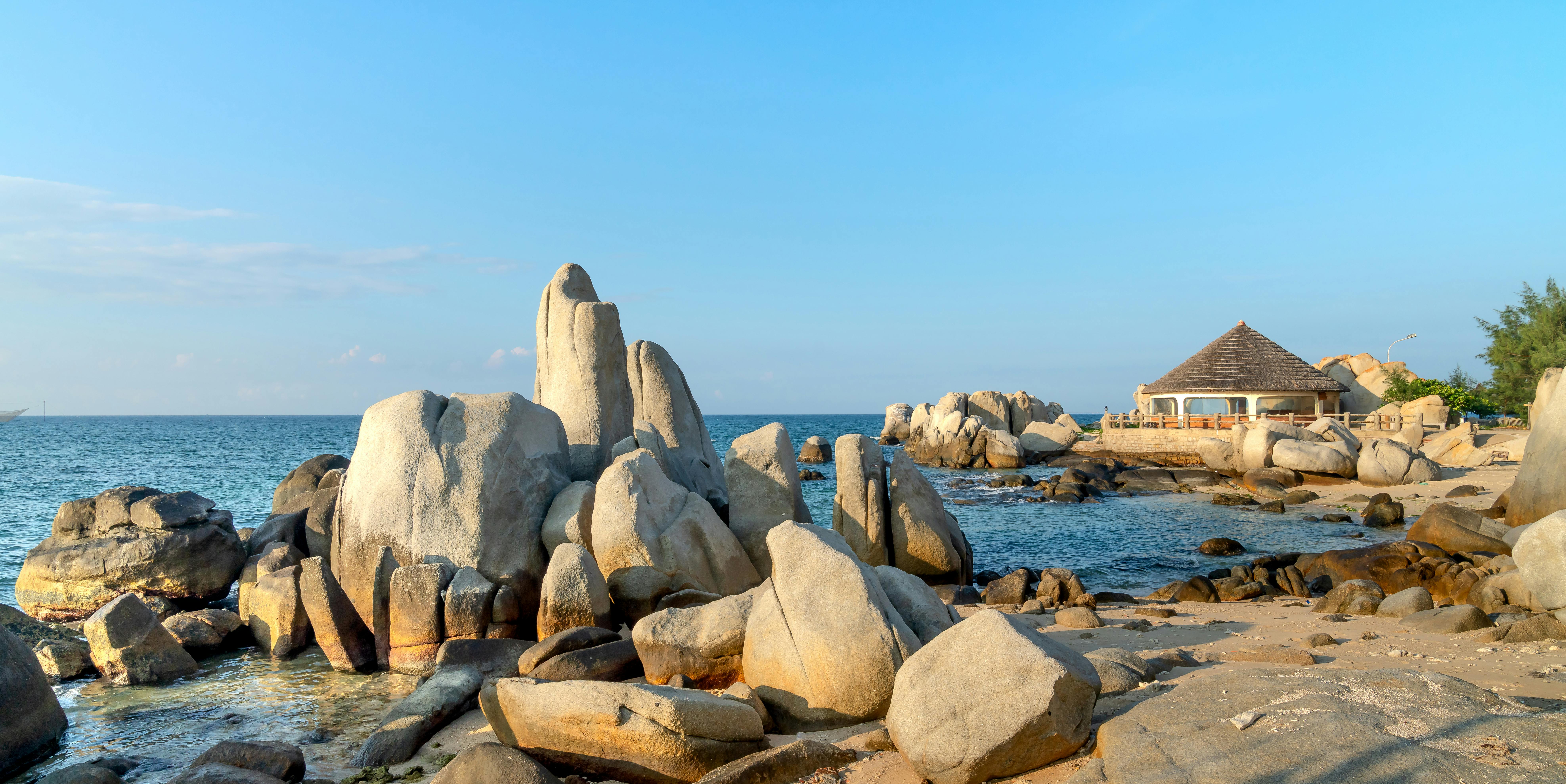 Boulders and Rocks on Shoreline Under a Clear Blue Sky · Free Stock Photo